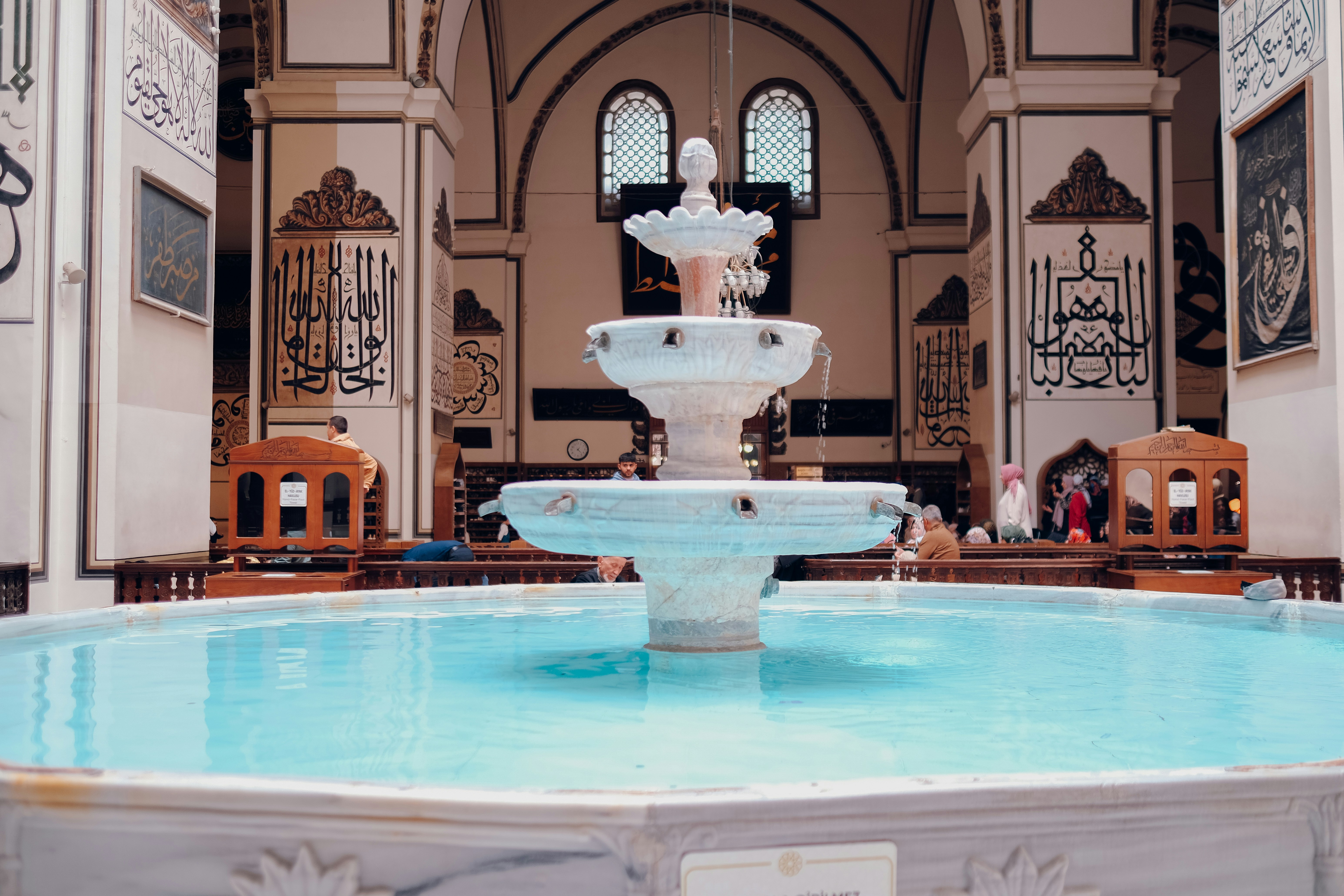 Symmetry in Marble: A Central Fountain Between Archways and Calligraphy
