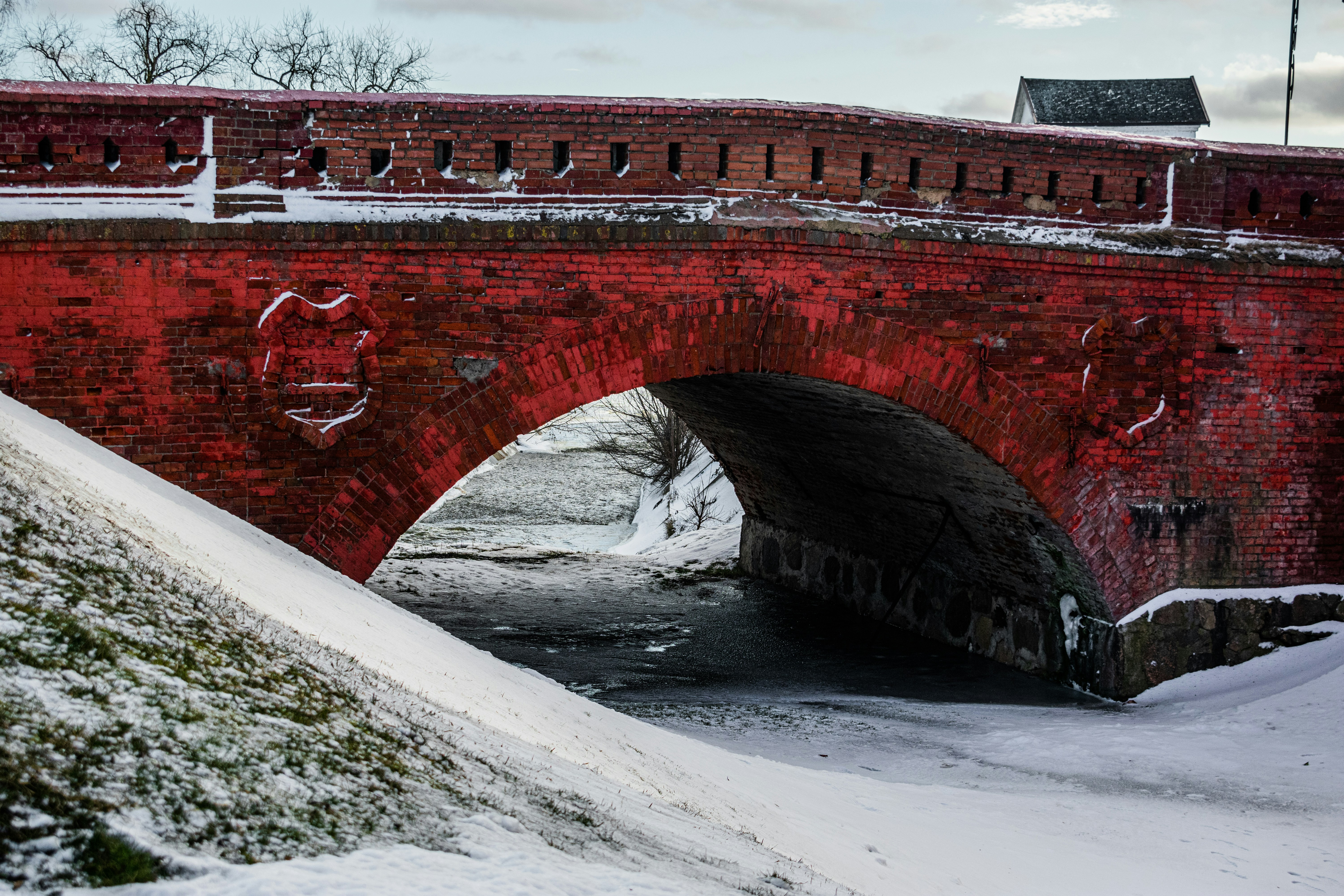 A red brick bridge over a river with snow on the ground photo – Free ...