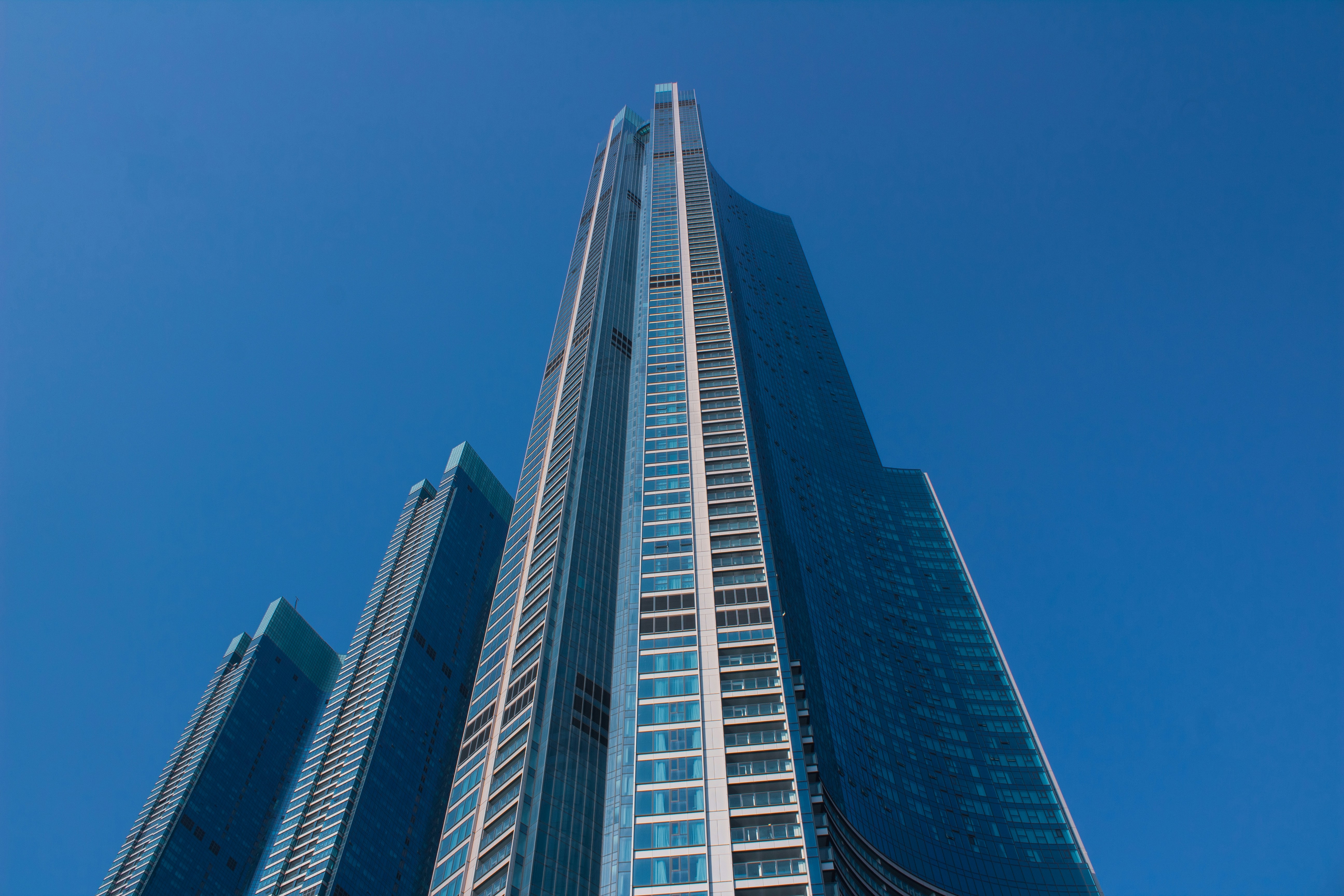 A very tall building towering over a city photo – Free Busan Image on ...