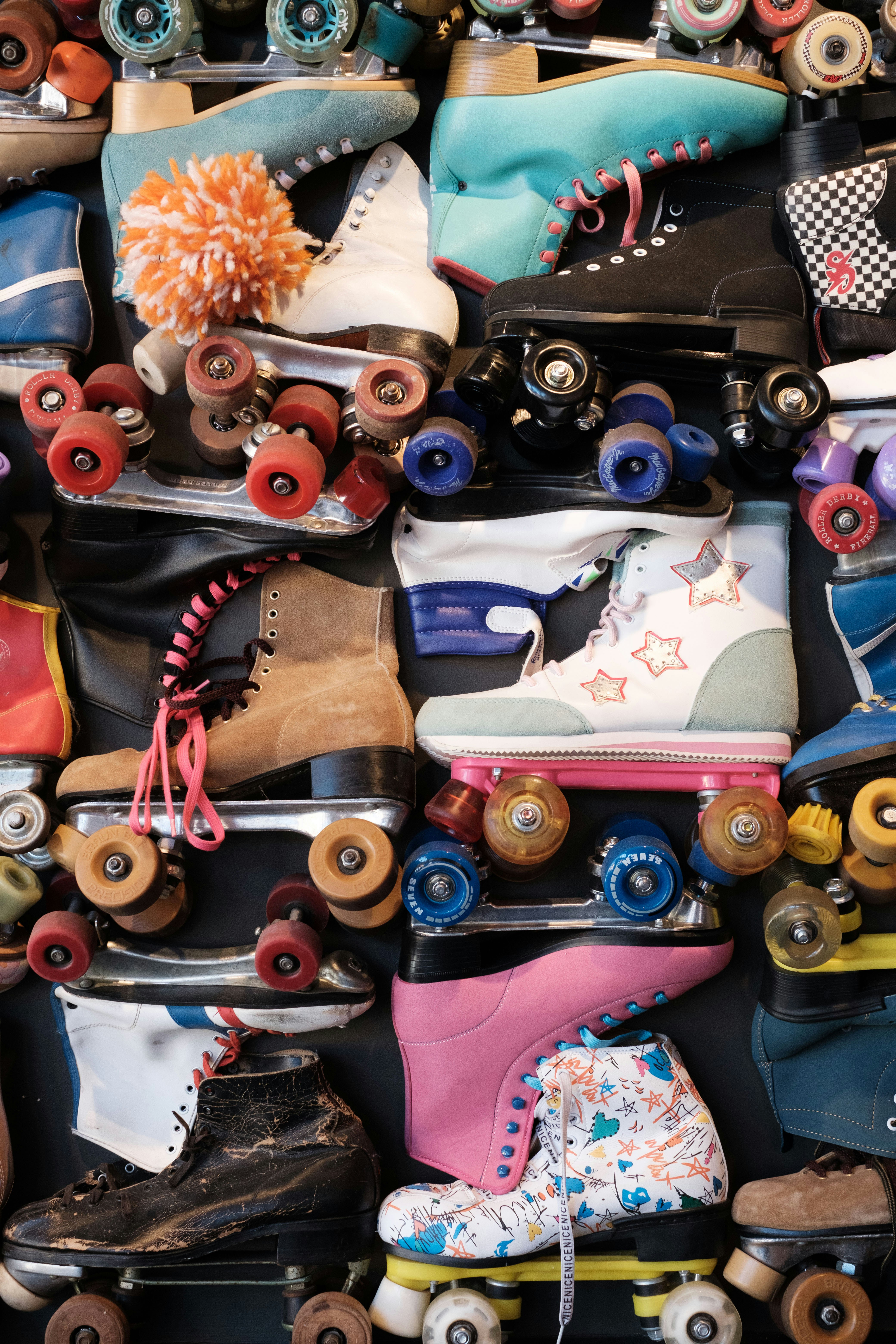 A pile of skateboards and roller skates all stacked on top of each ...
