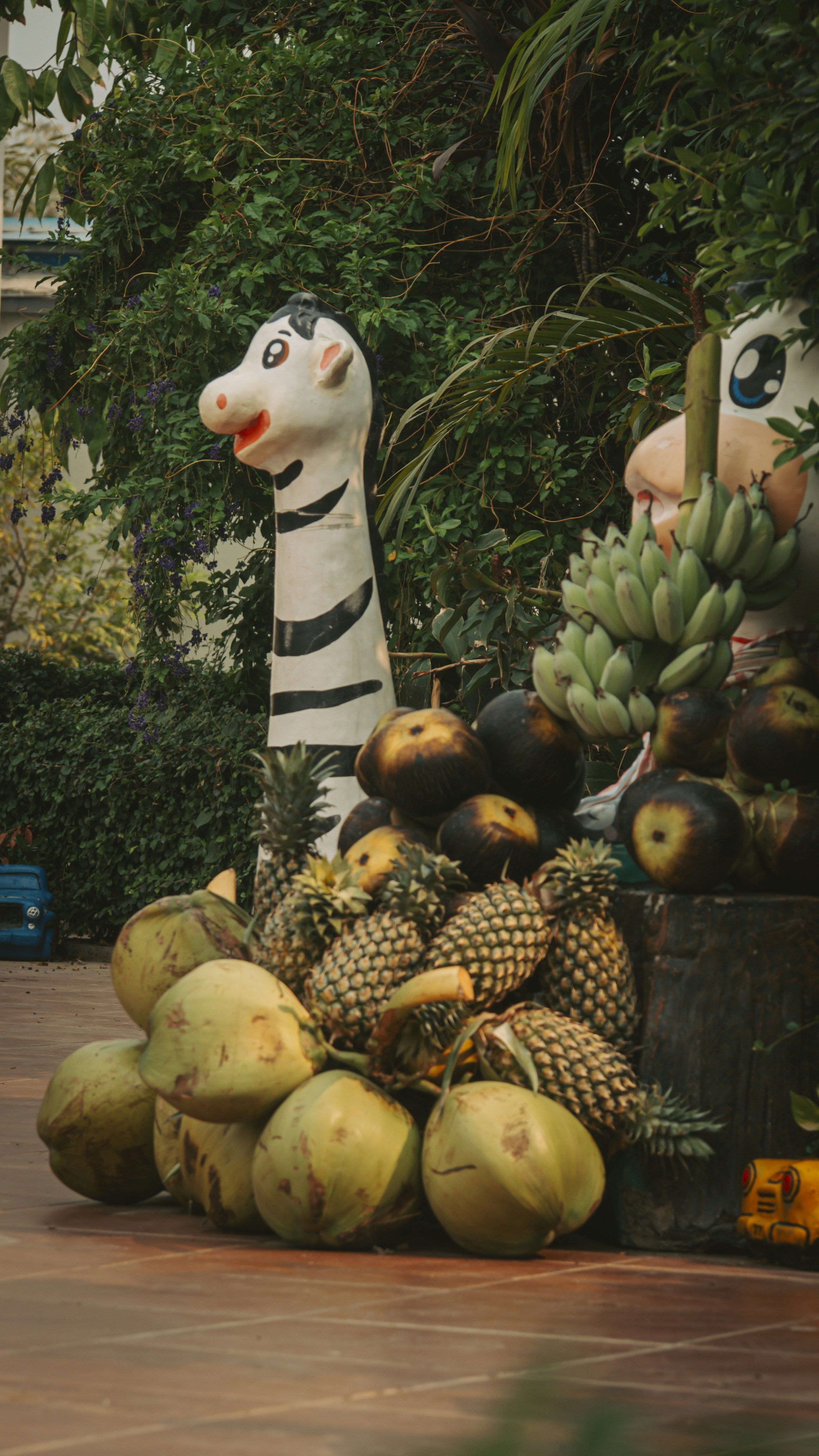 Zebra Sculpture Guards a Fruit Heap in a Lush Courtyard