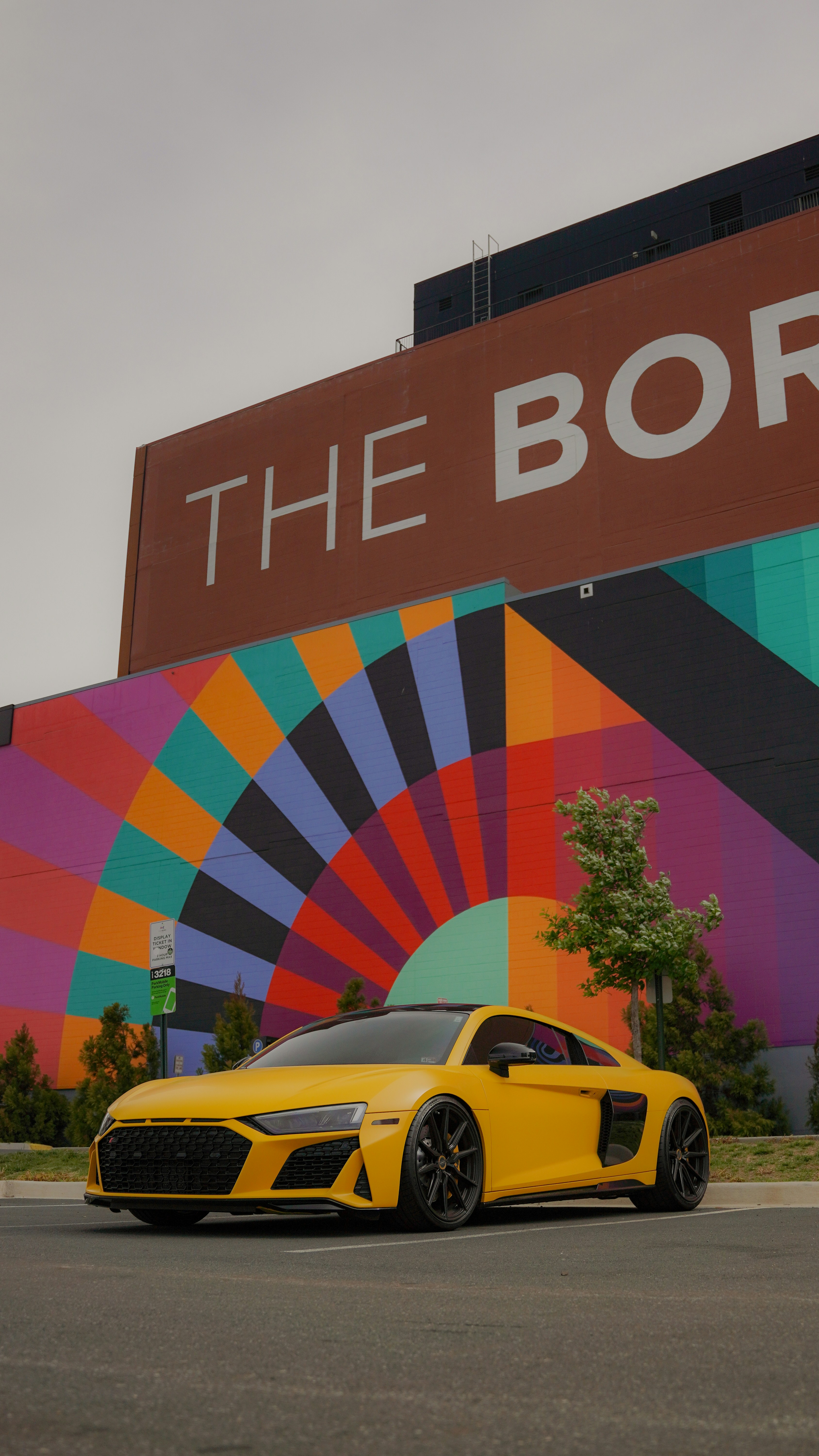 Un auto deportivo amarillo estacionado frente a un colorido edificio ...