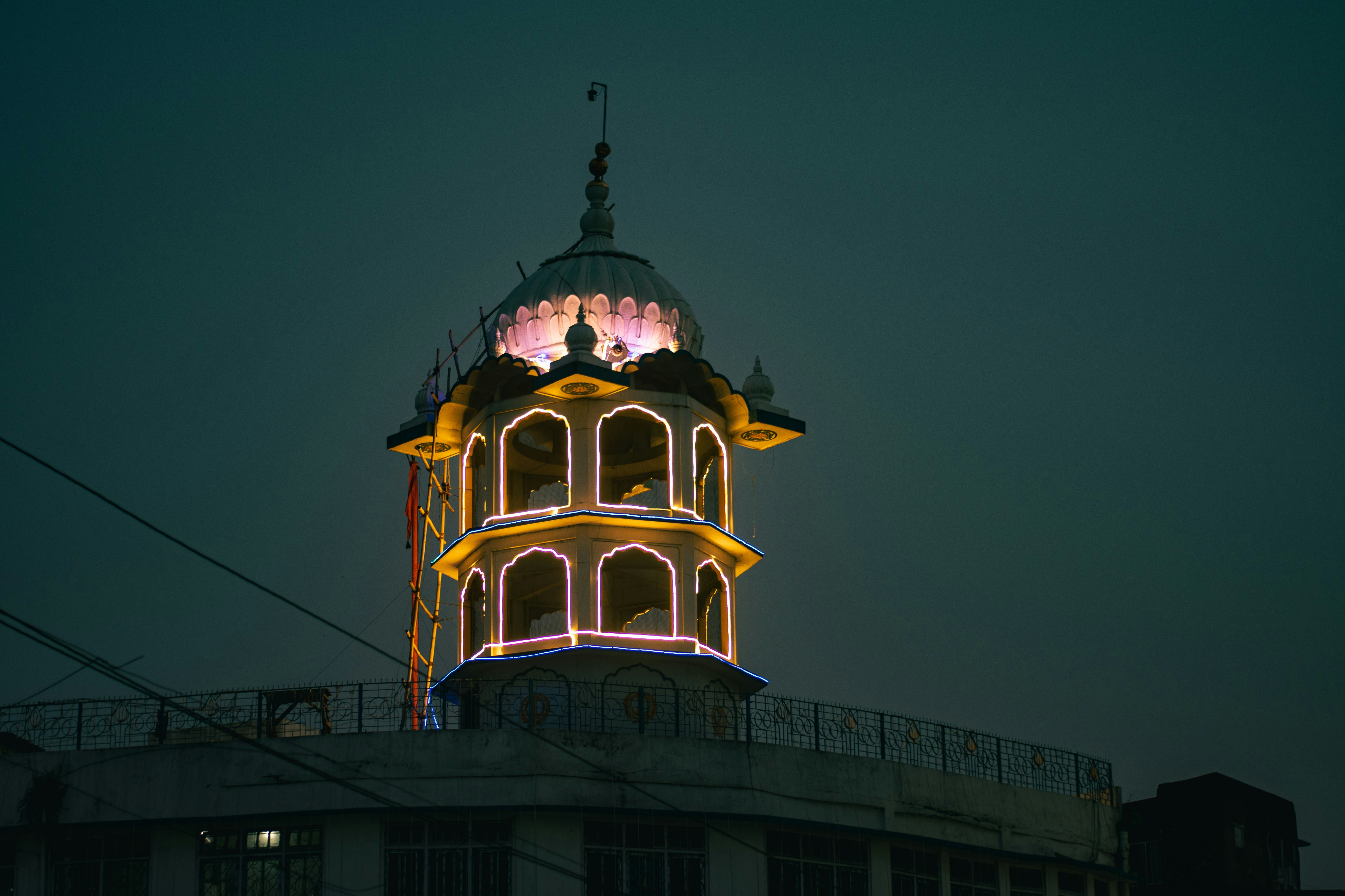 A building with a lit up tower at night photo – Free Assam Image on ...