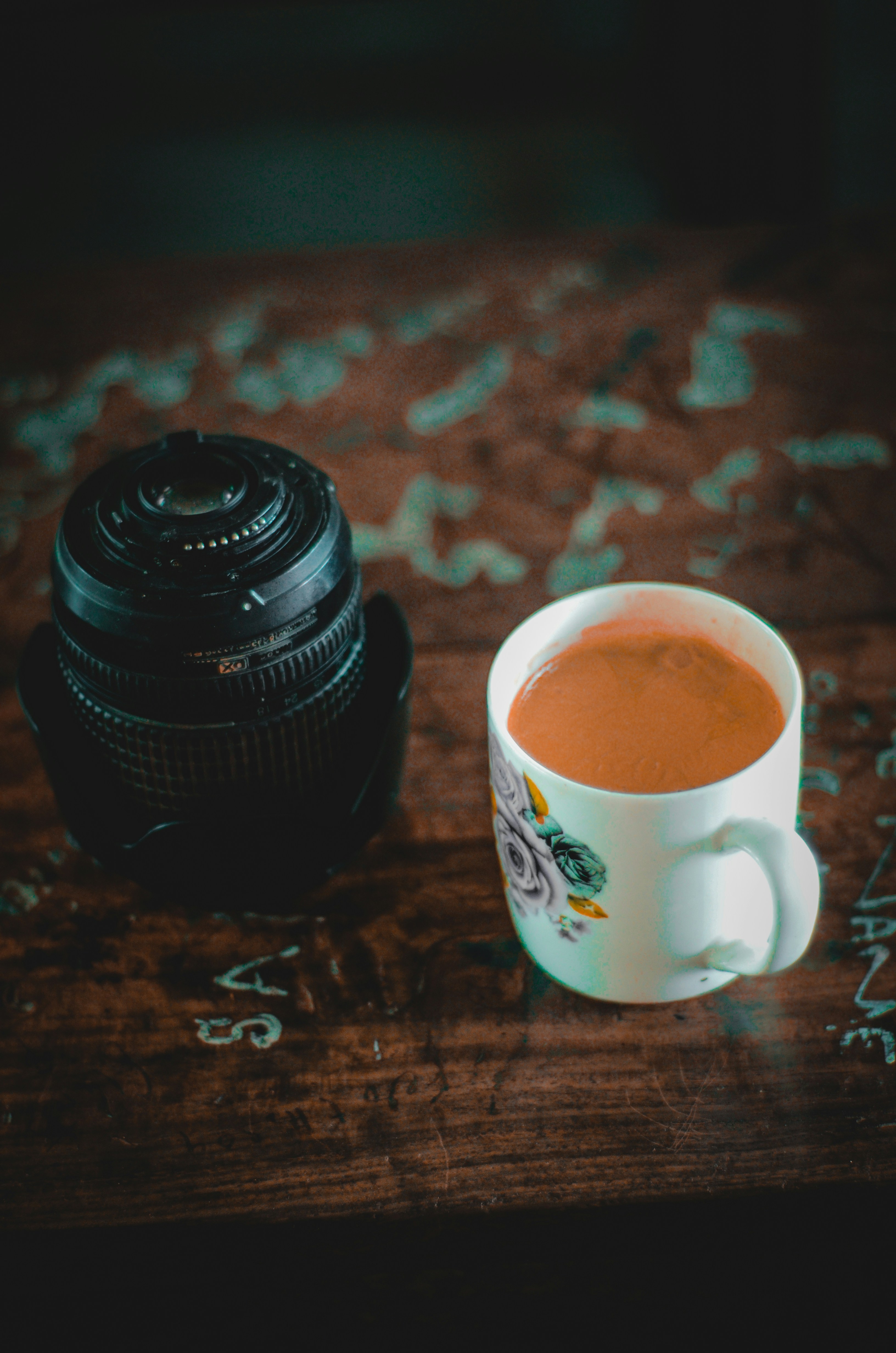 Between Steel and Steam: A Lens Beside a Coffee Cup on a Weathered Table