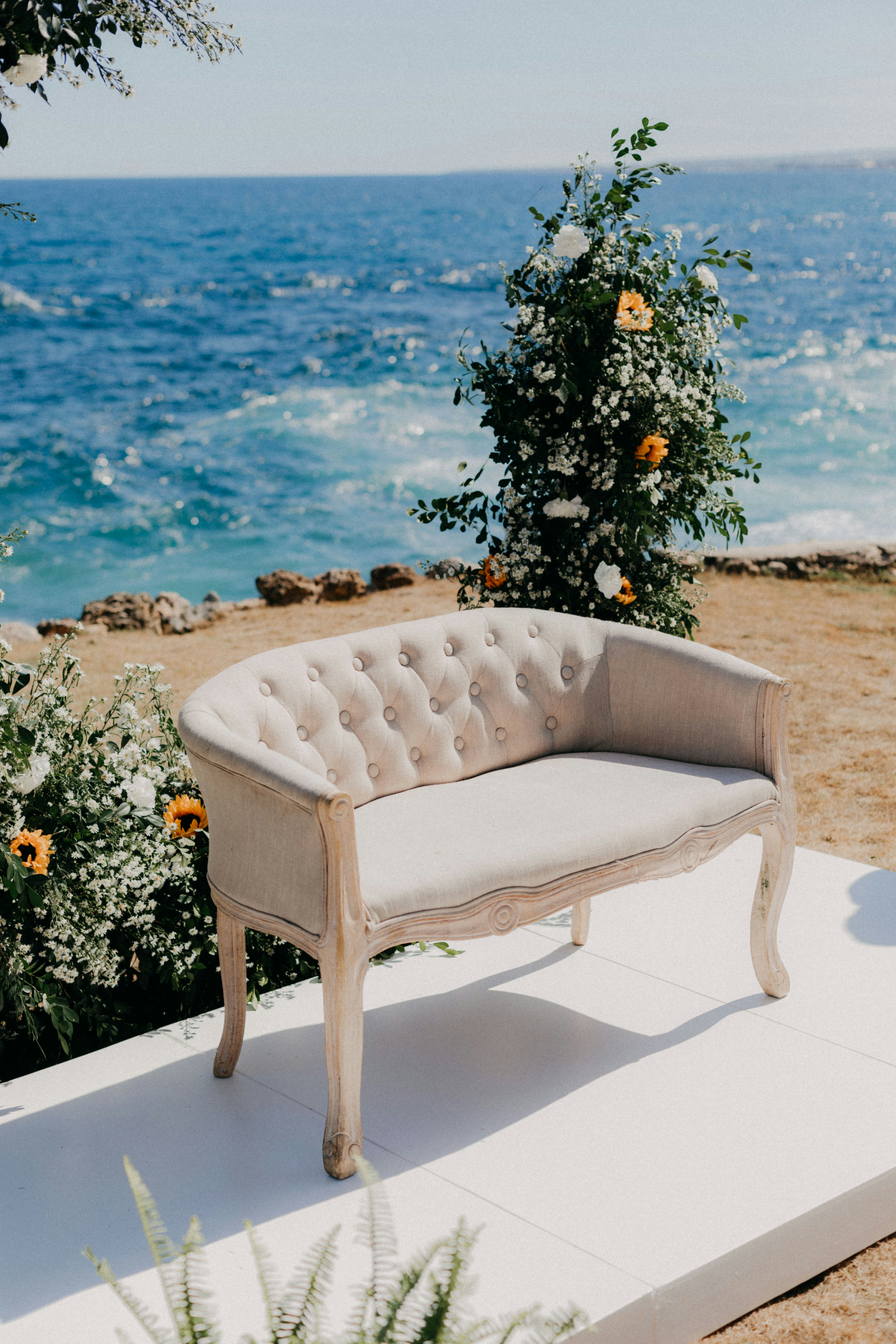 Seafront seating under floral arch gracefully framed by ocean horizon