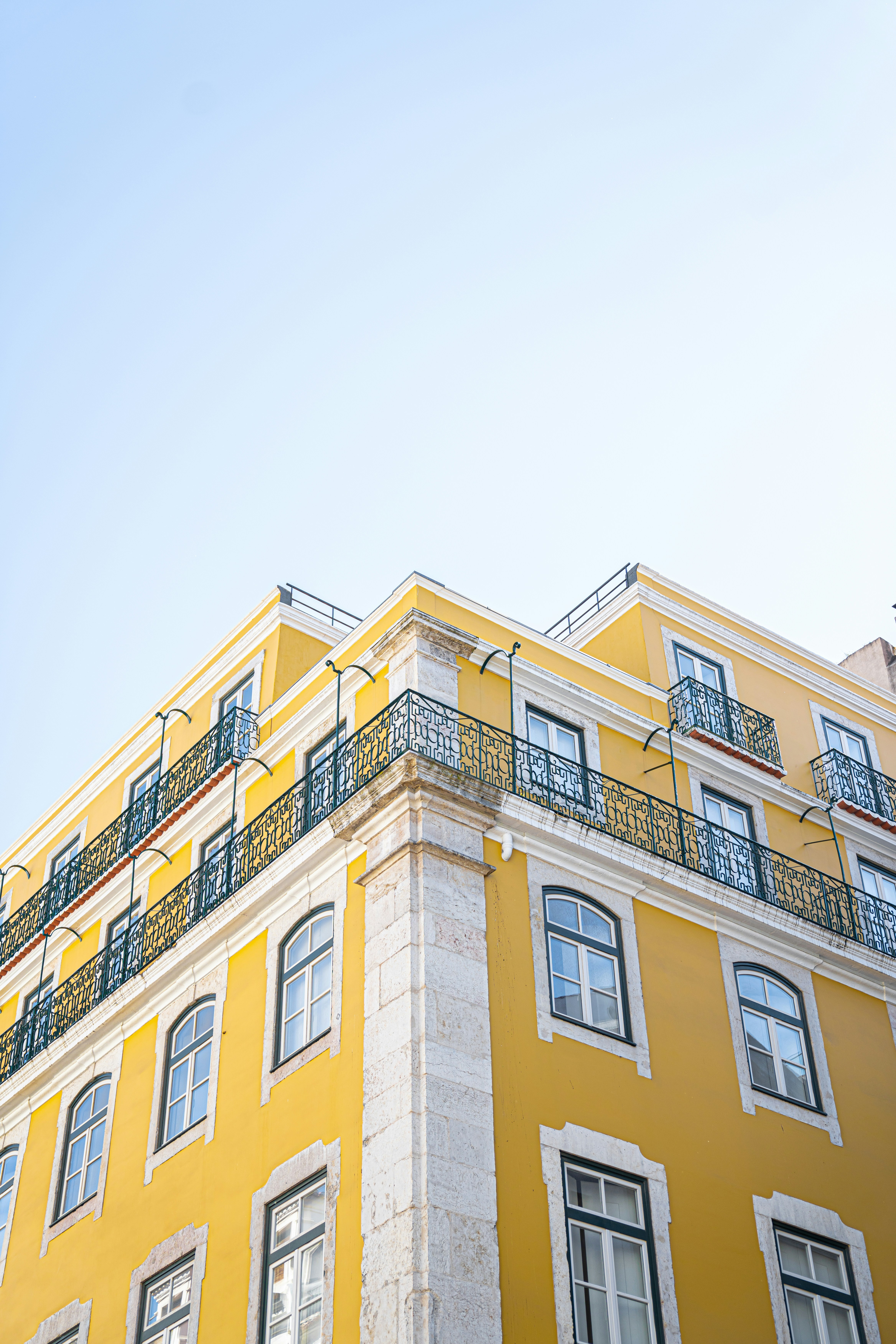 A tall yellow building with balconies on top of it photo – Free ...