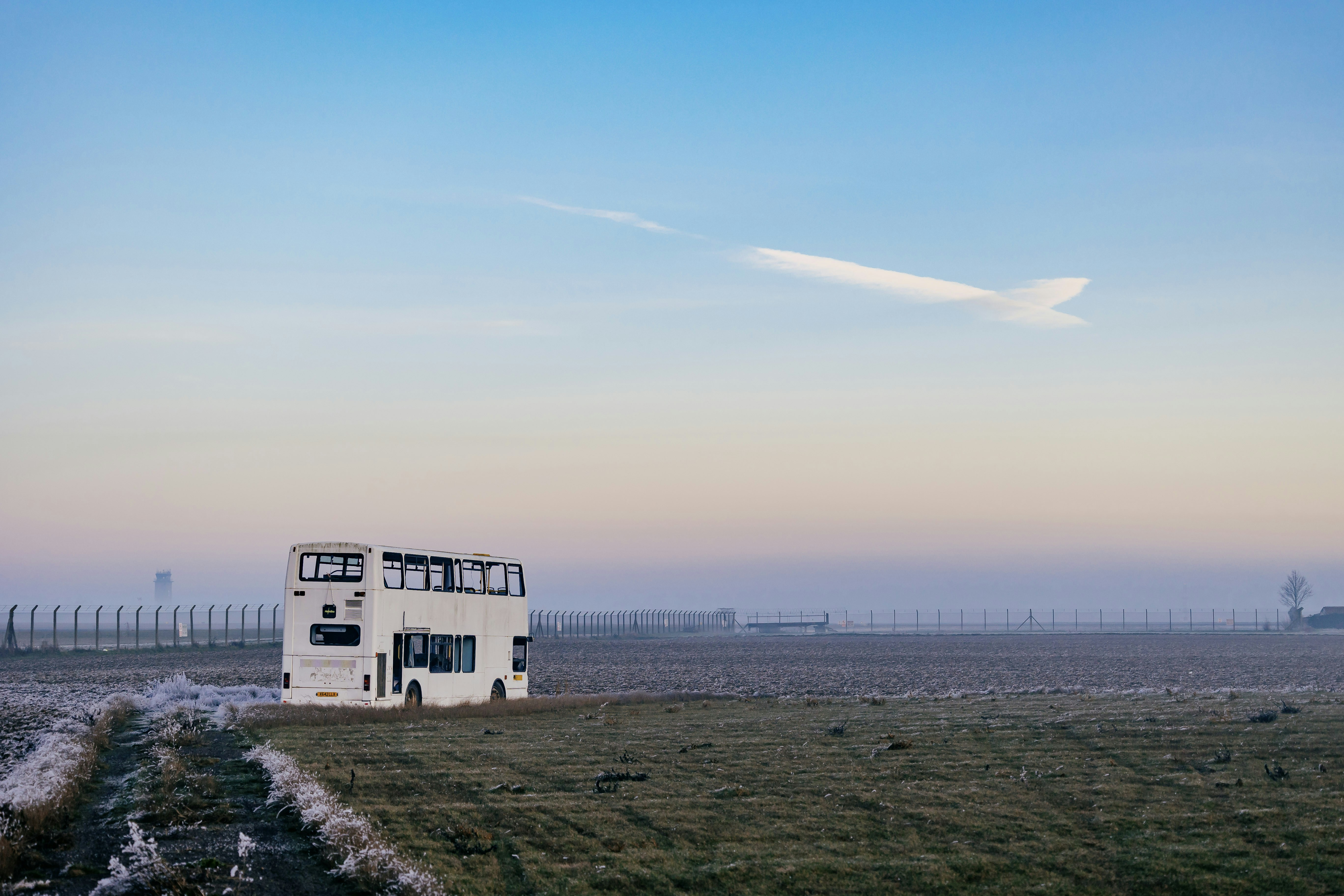 A white double decker bus driving down a road photo – Free Sunset Image ...