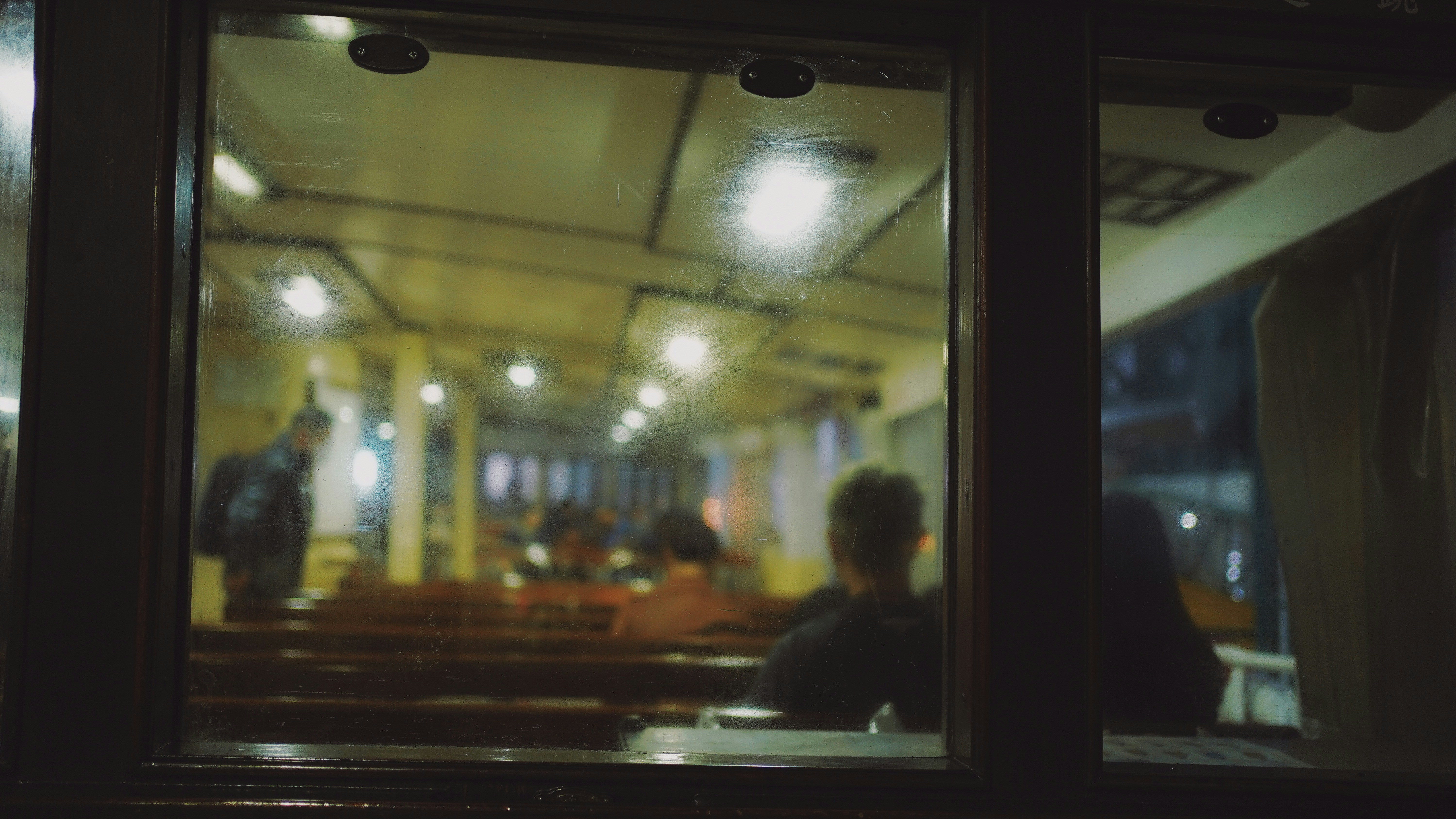 Windowed Quiet: Blurred Figures Inside a Neon-Warmed Transit Car