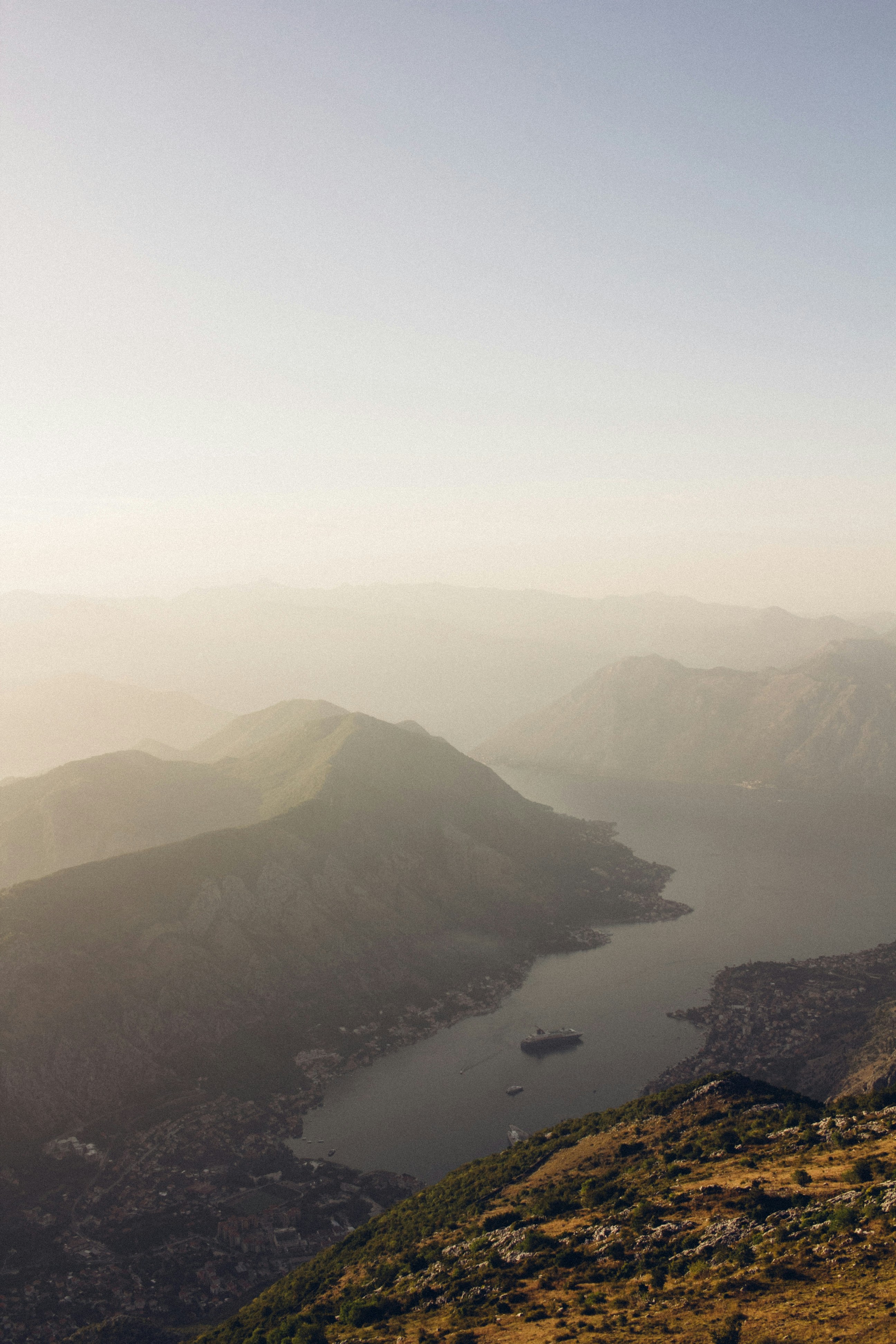 Mist-Laced Inlet: A Lone Vessel Amid Quiet Hills