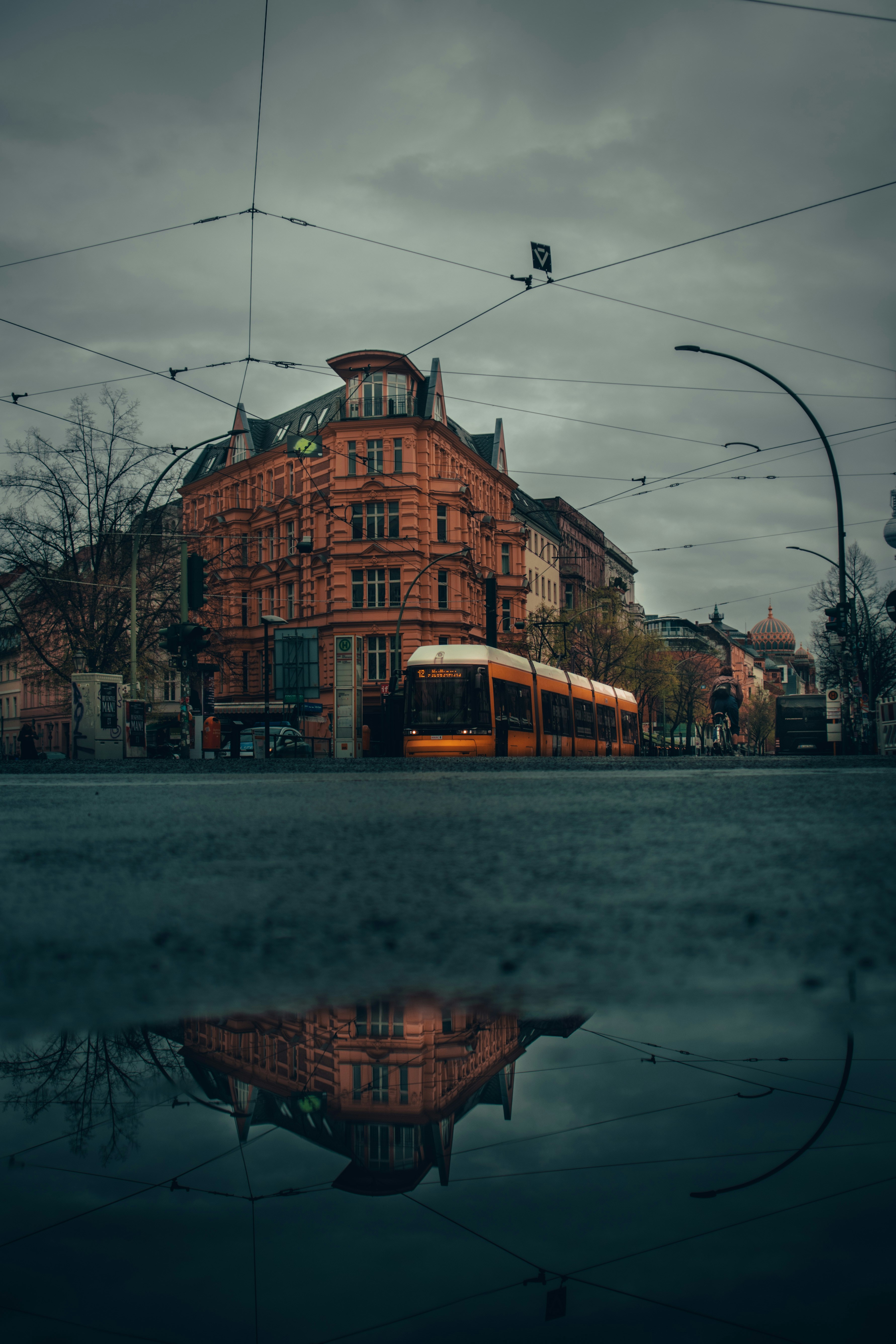 Orange Tram at a Brick-Lined Boulevard Under a Brooding Cloudscape
