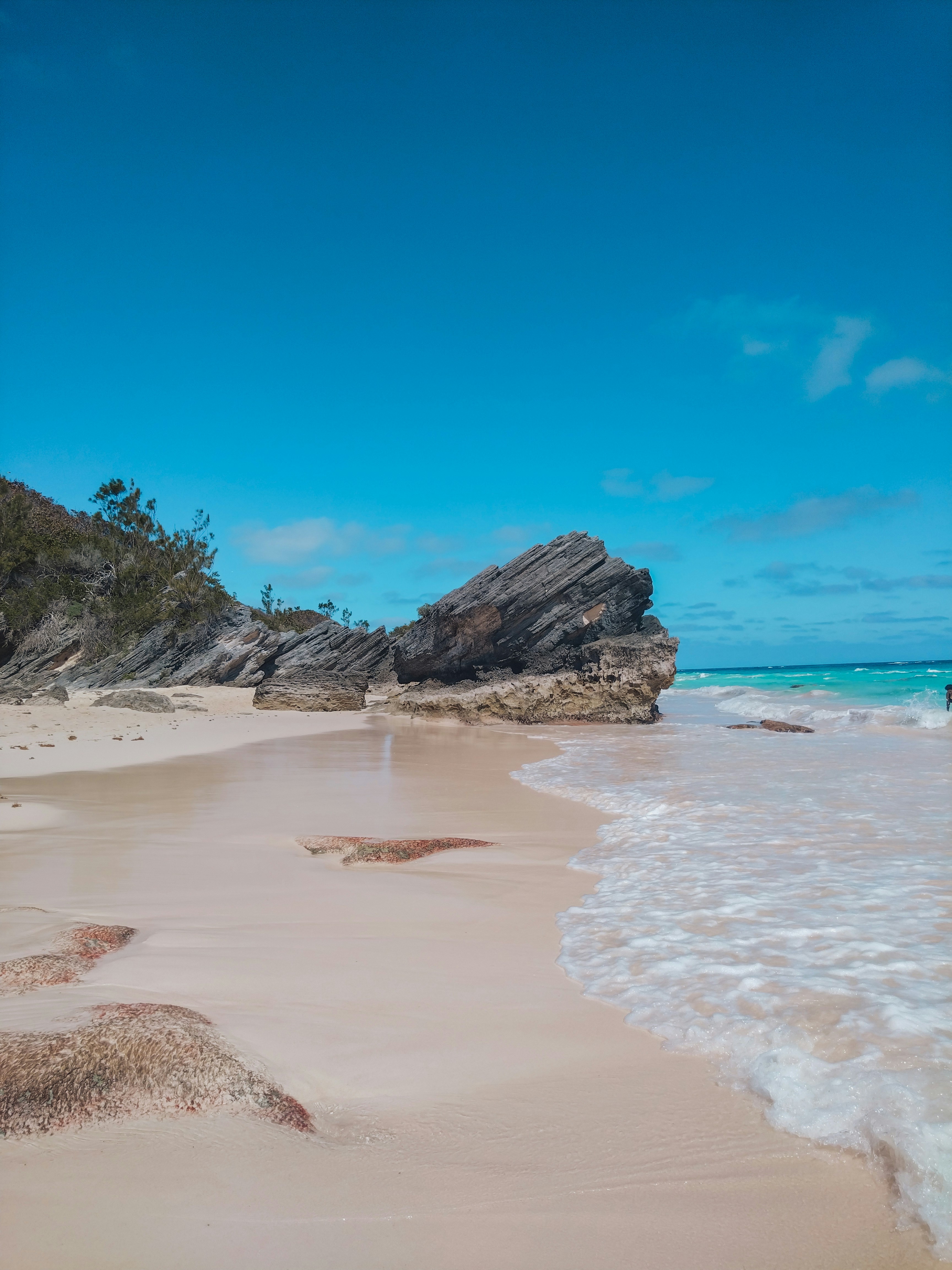 A sandy beach with a rock formation in the background photo – Free ...