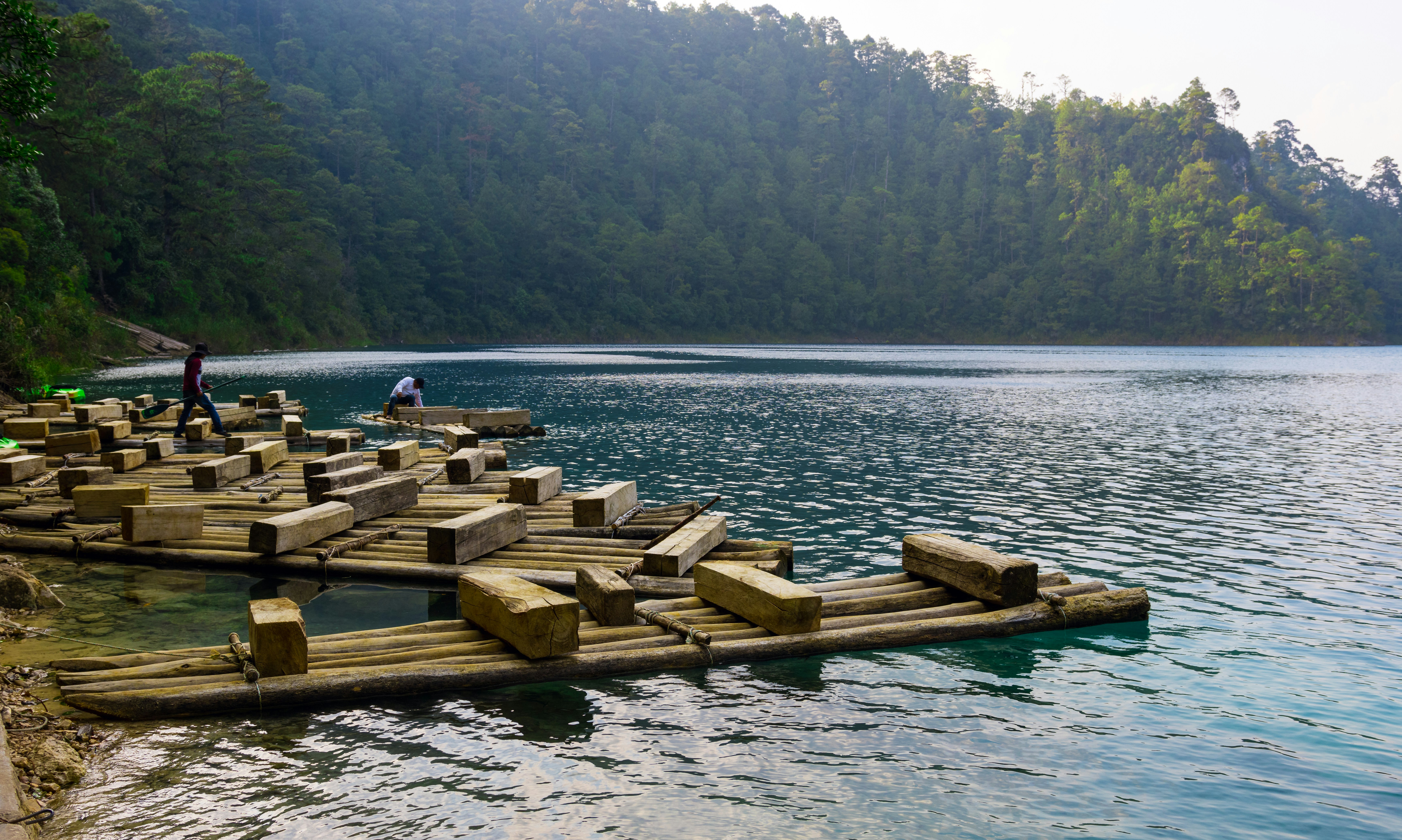 A group of people standing on wooden rafts in the water photo – Free ...