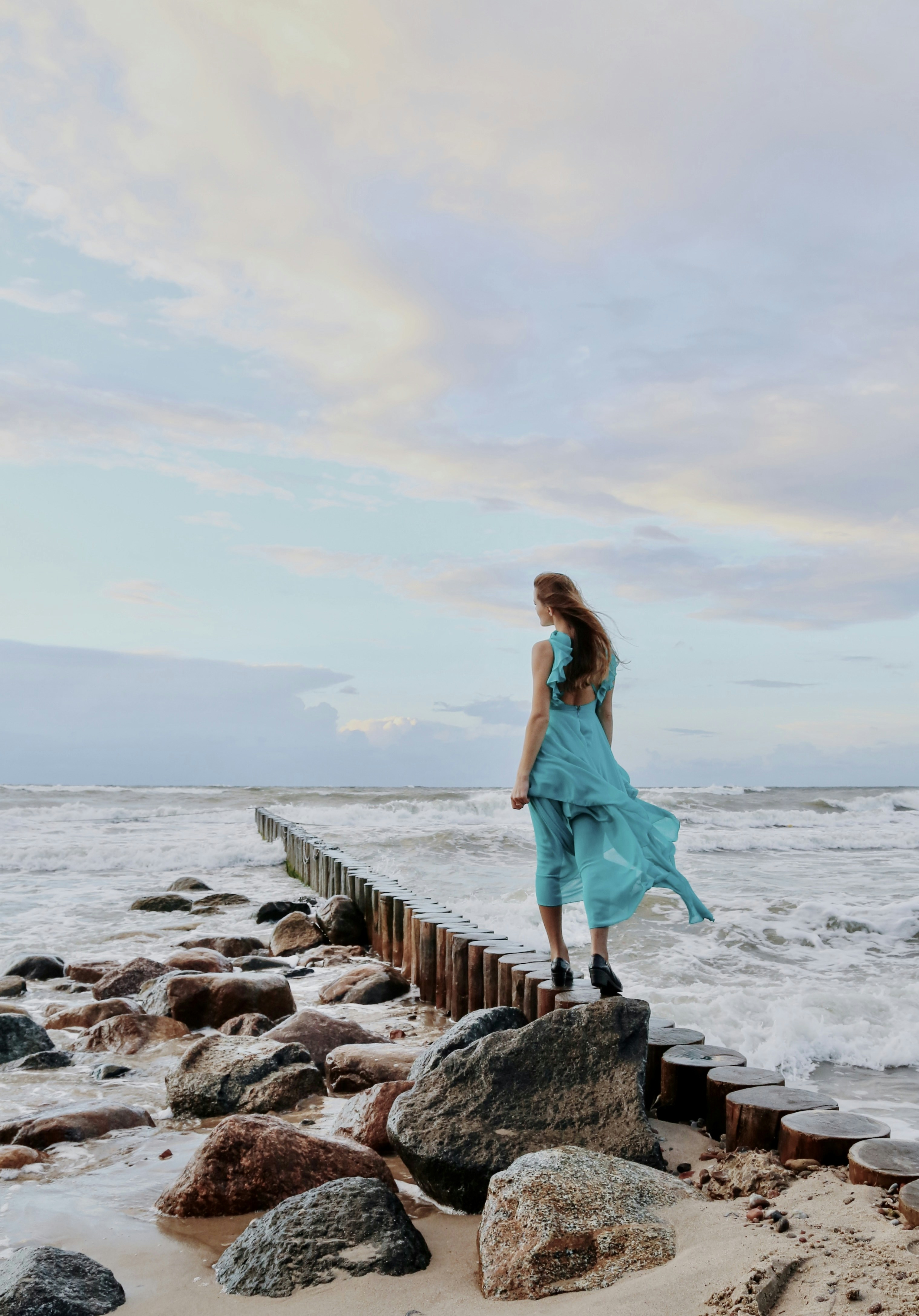 A woman in a blue dress standing on a wooden pier photo – Free ...