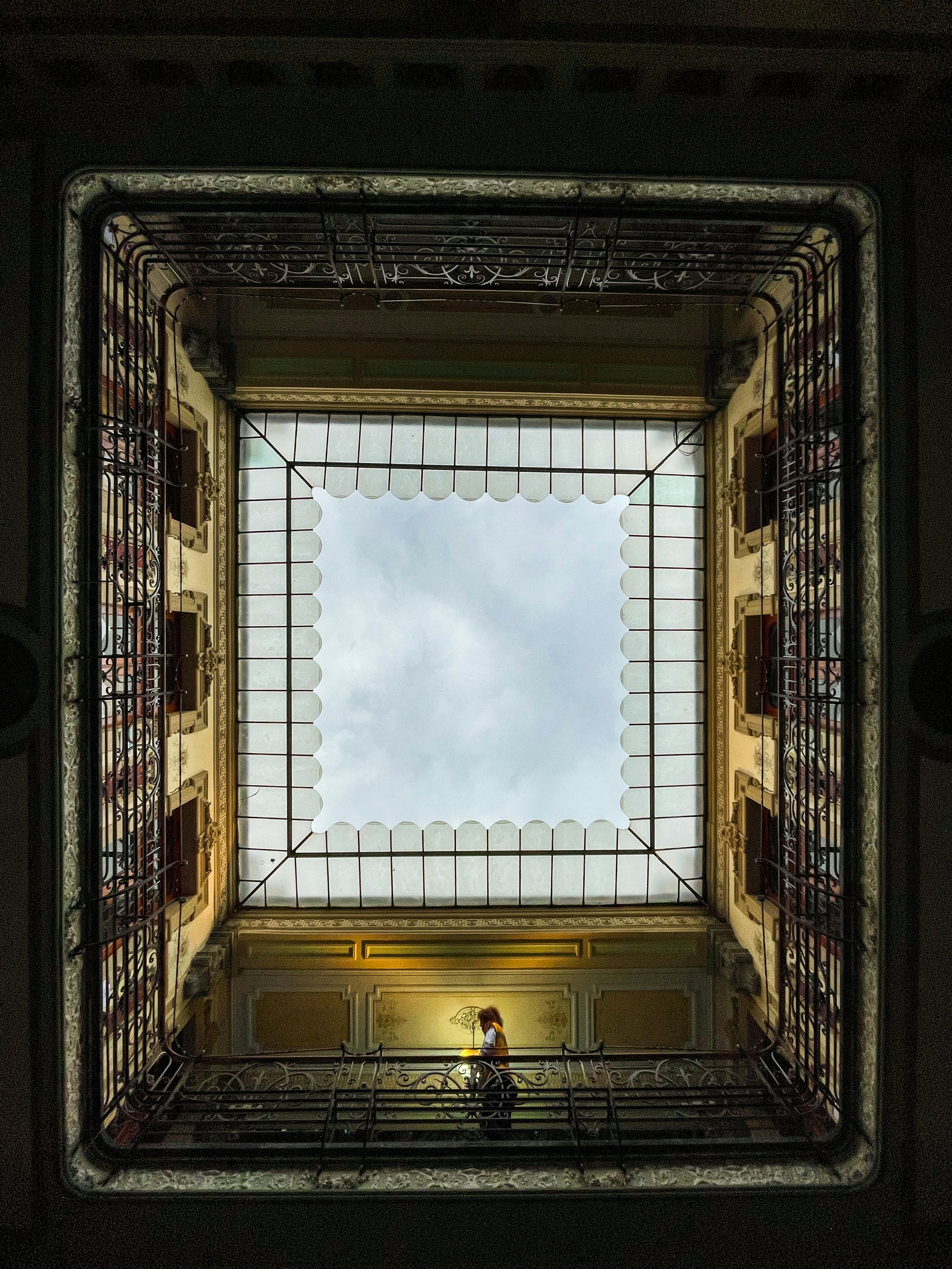 A person sitting on a bench in a room with a skylight photo – Free ...