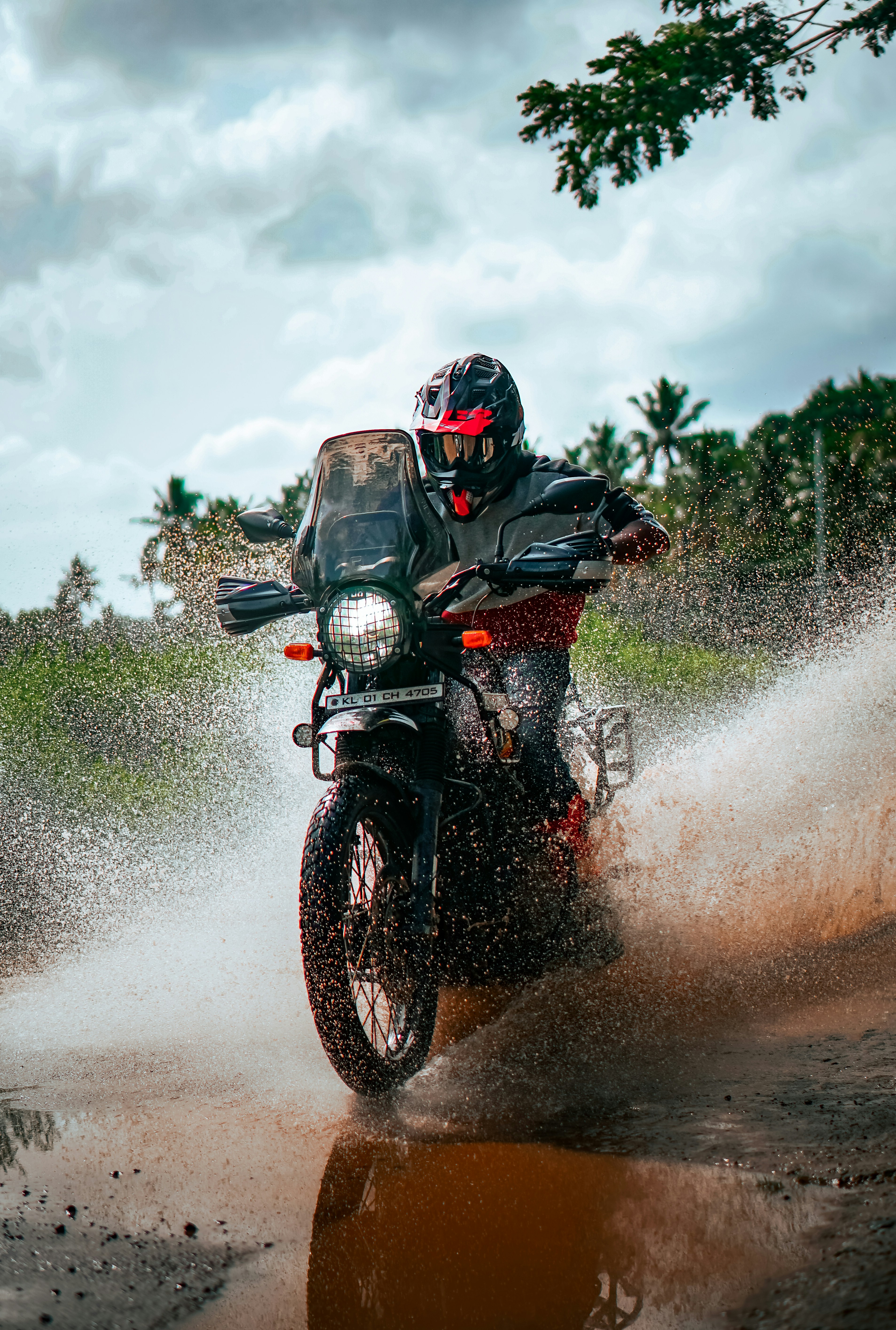 A man riding a motorcycle through a puddle of water photo – Free ...