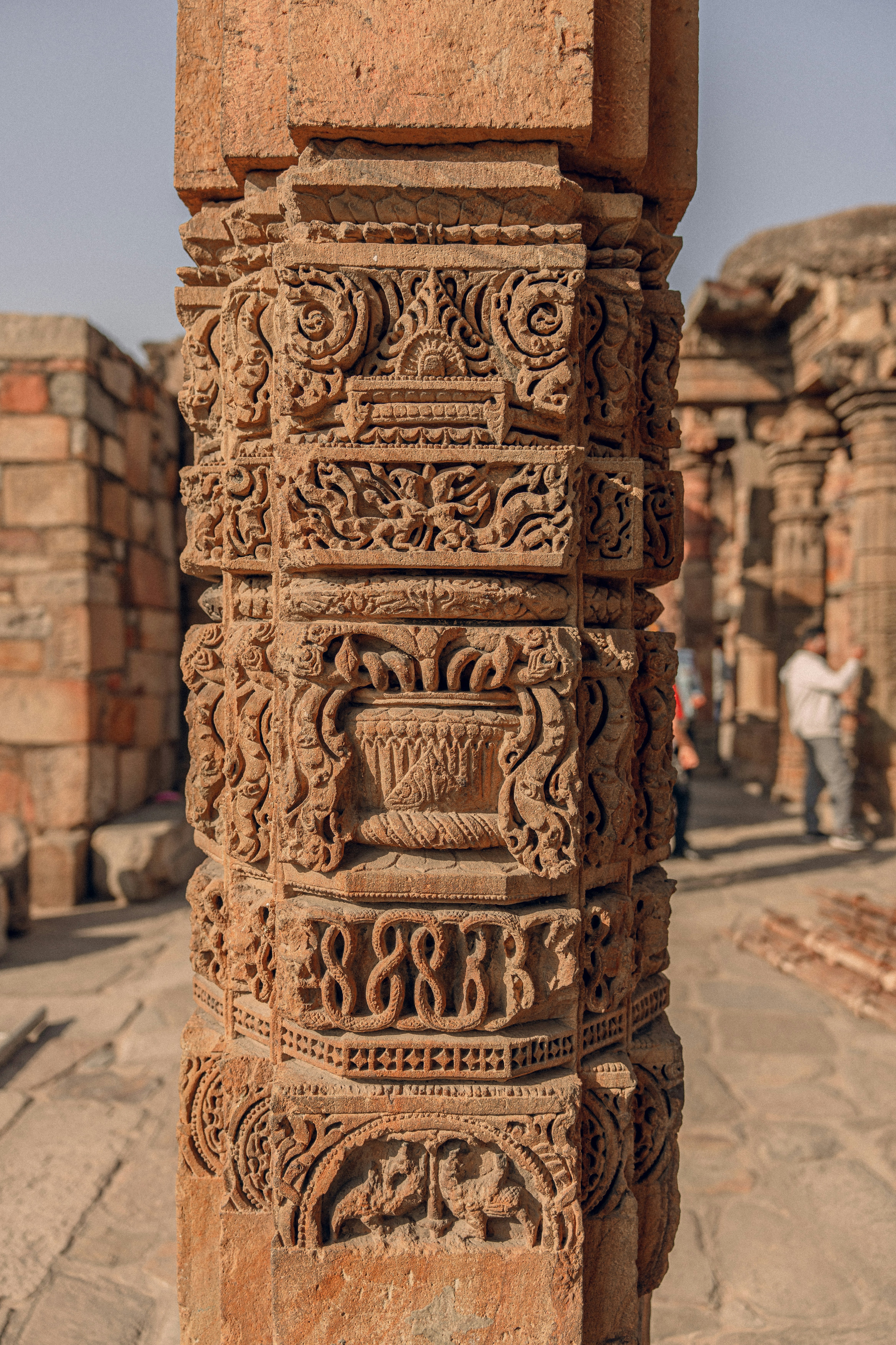 Intricate sandstone column carved with spiraling reliefs in sunlit ruin