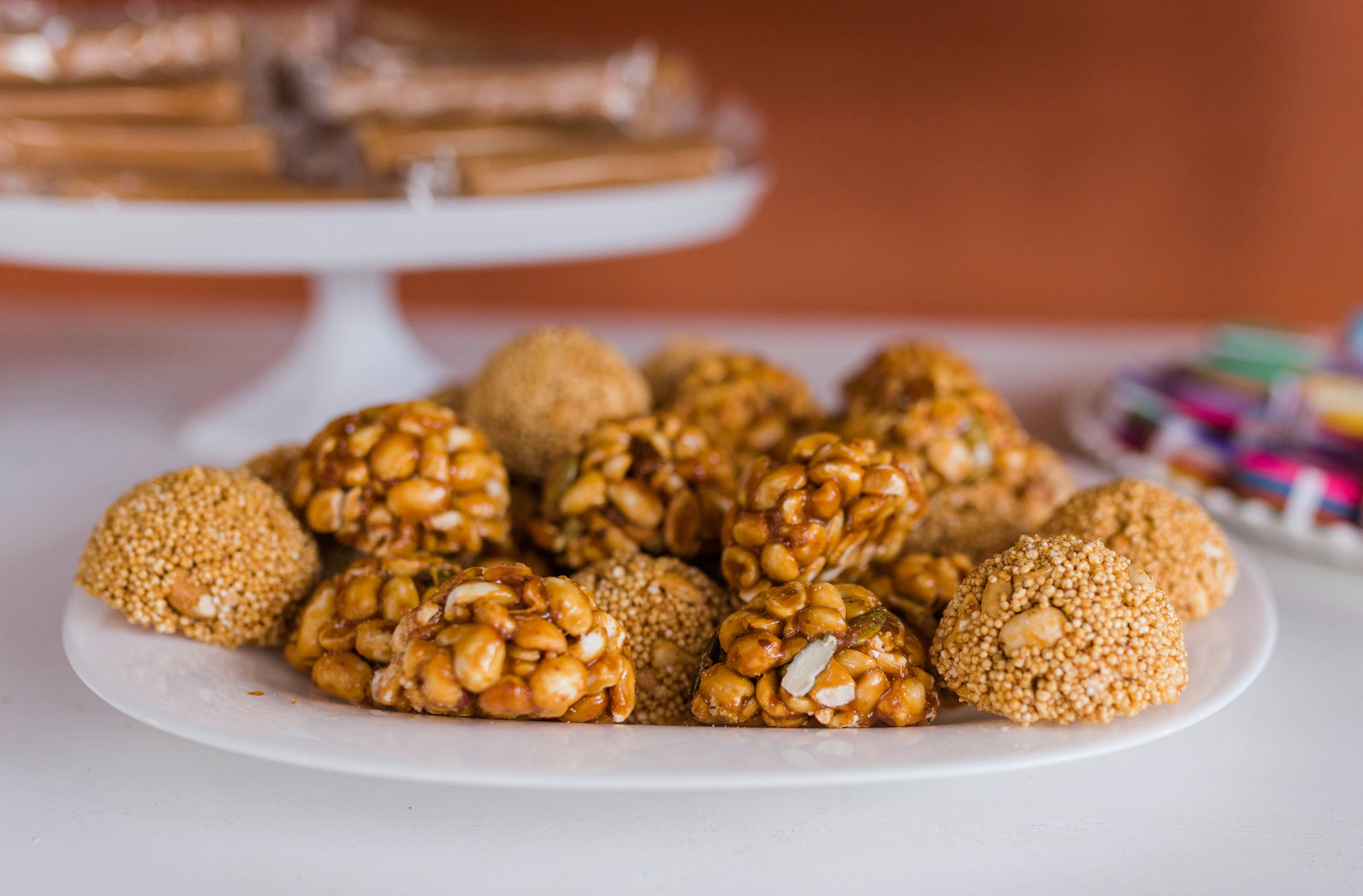 Golden bite-sized treats: sesame-coated and peanut clusters on a white platter