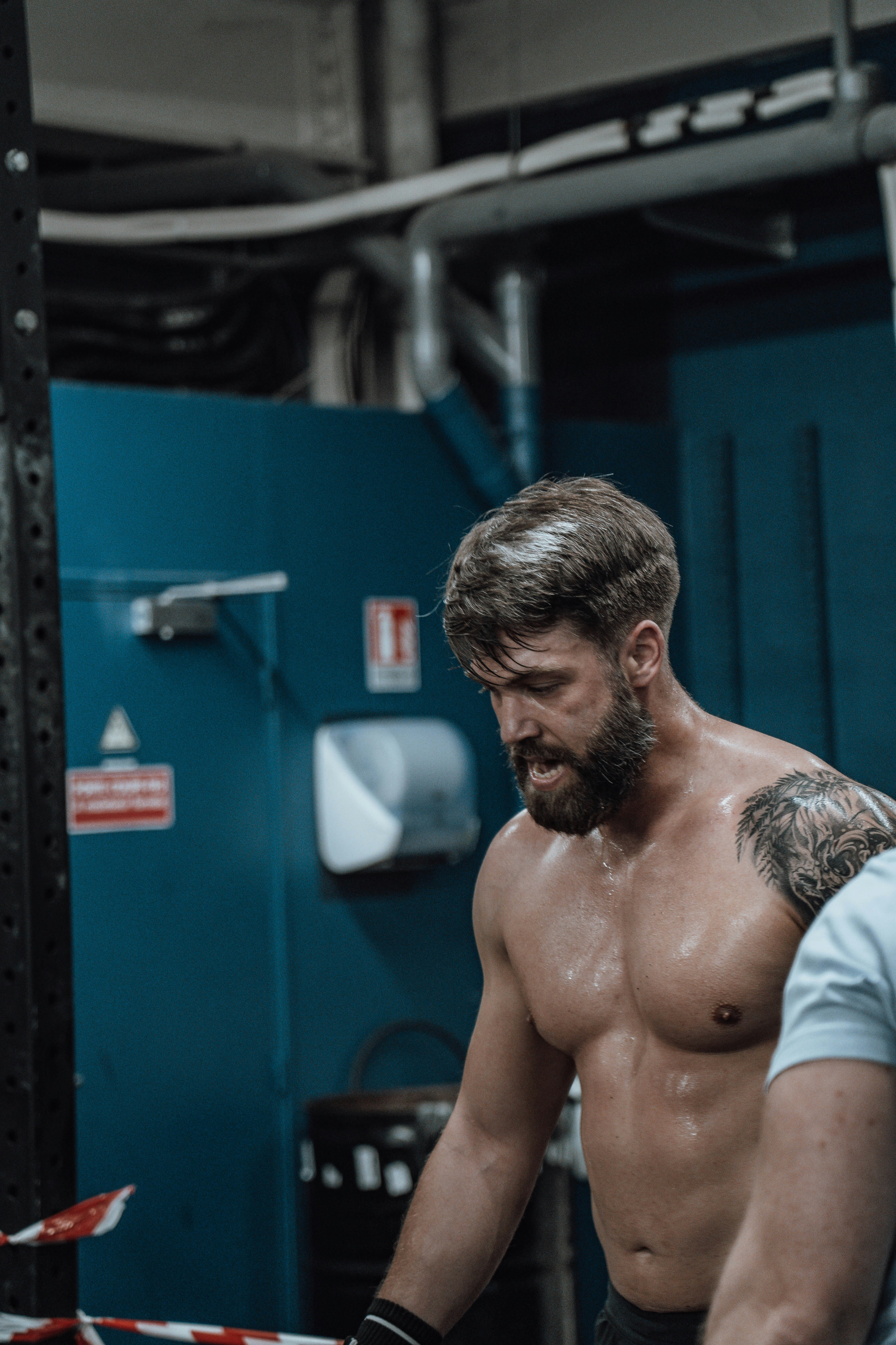 A shirtless man working on a machine in a factory photo – Free Sweating ...