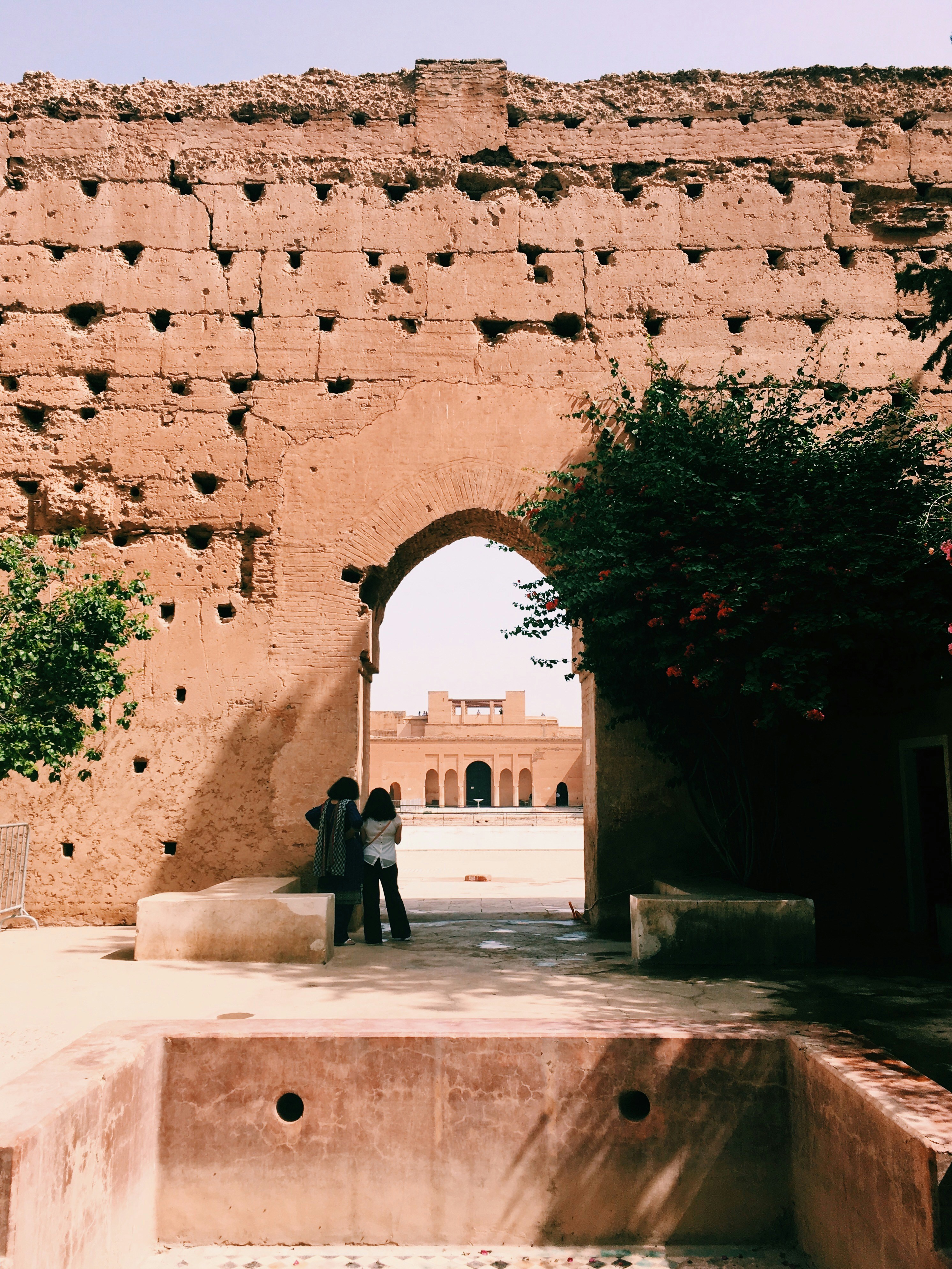 Sunlit Archway Courtyard: Travelers Pause at the Desert Fortress Gate