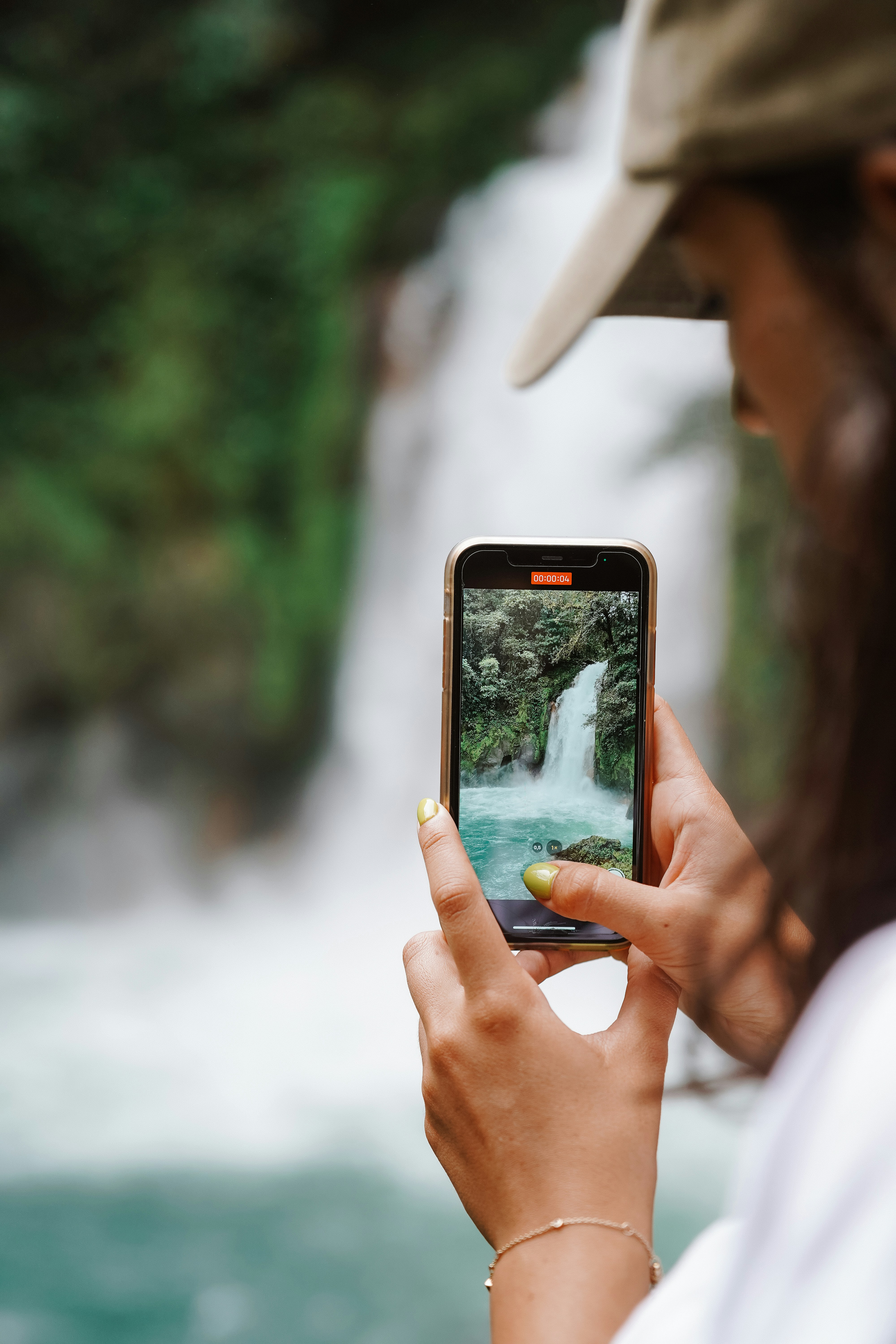 a woman taking a picture of a waterfall
