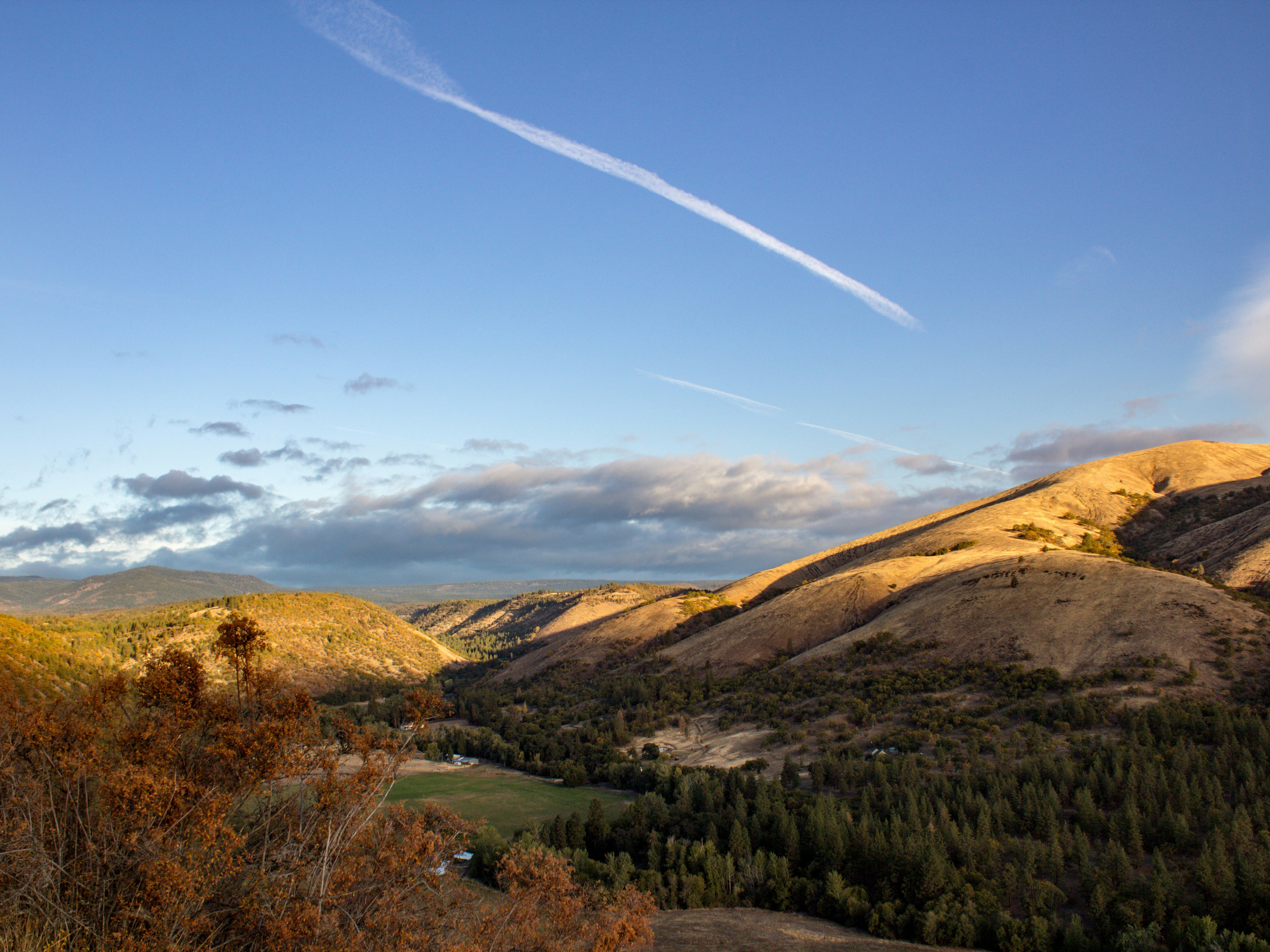 A view of a valley with trees and hills in the background photo – Free ...