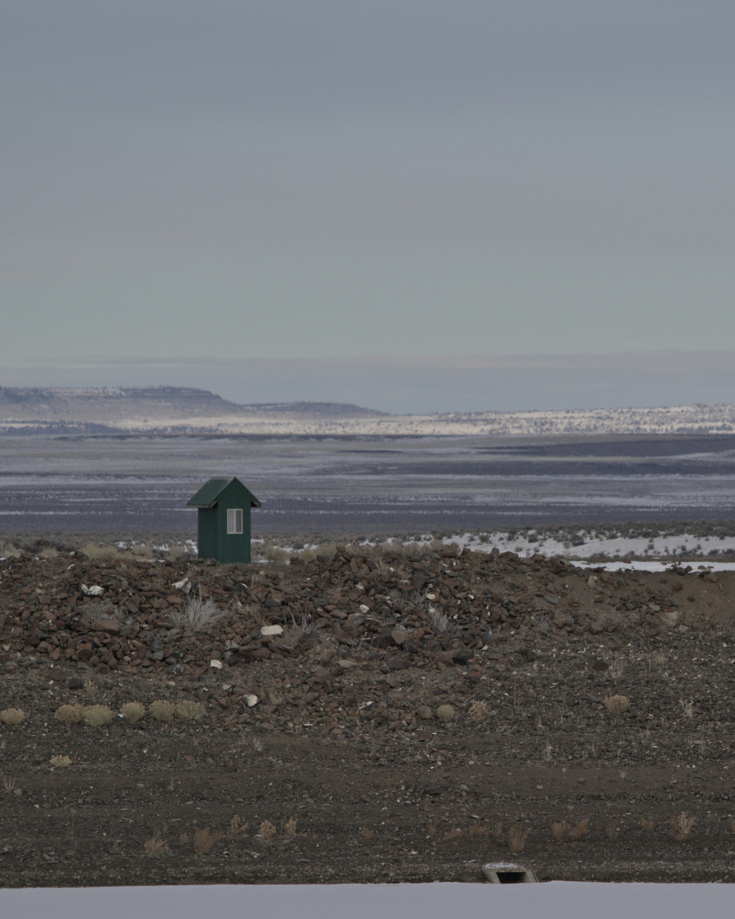 A small green building sitting on top of a rocky field photo – Free ...