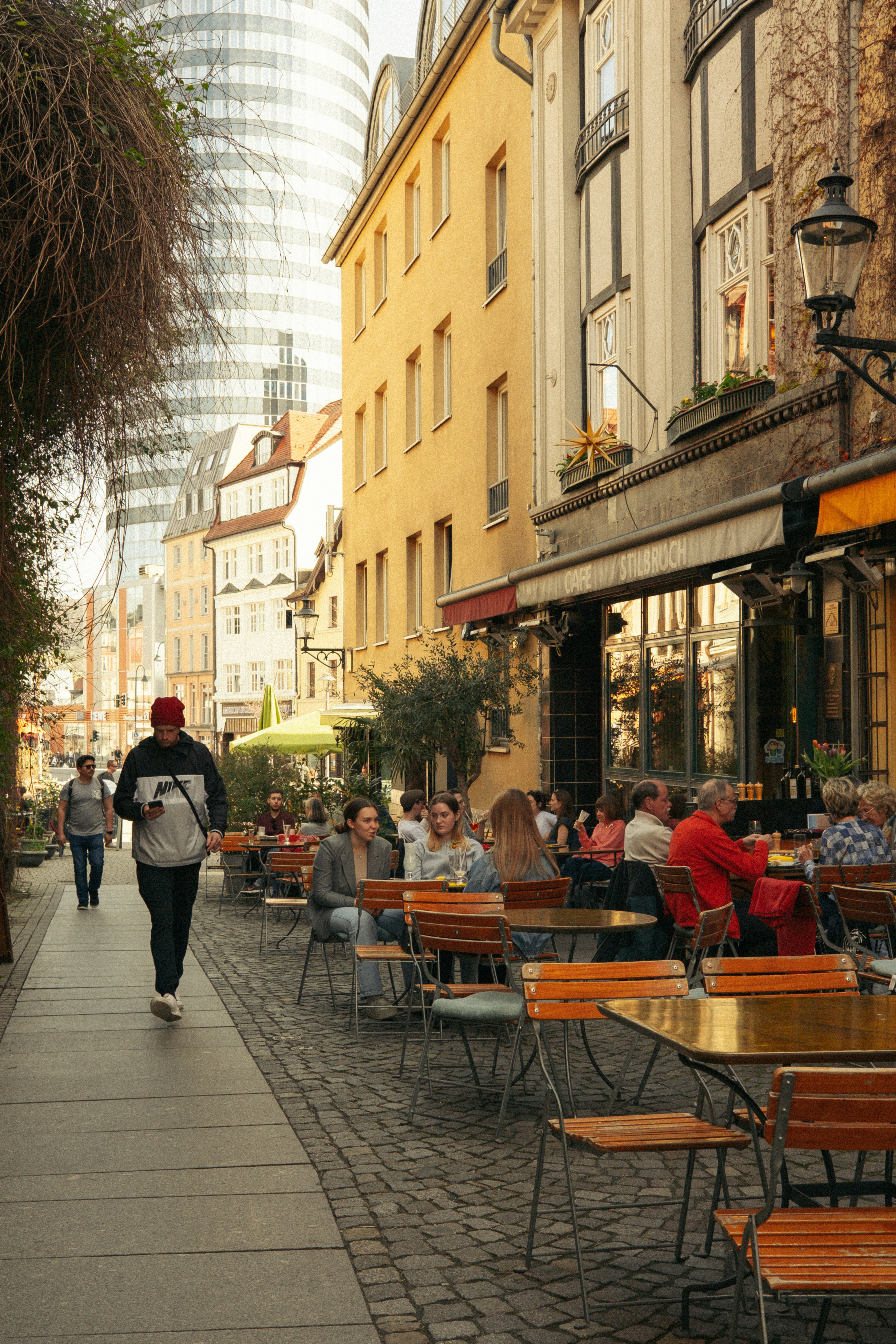 A man walking down a sidewalk next to tables and chairs photo – Free ...