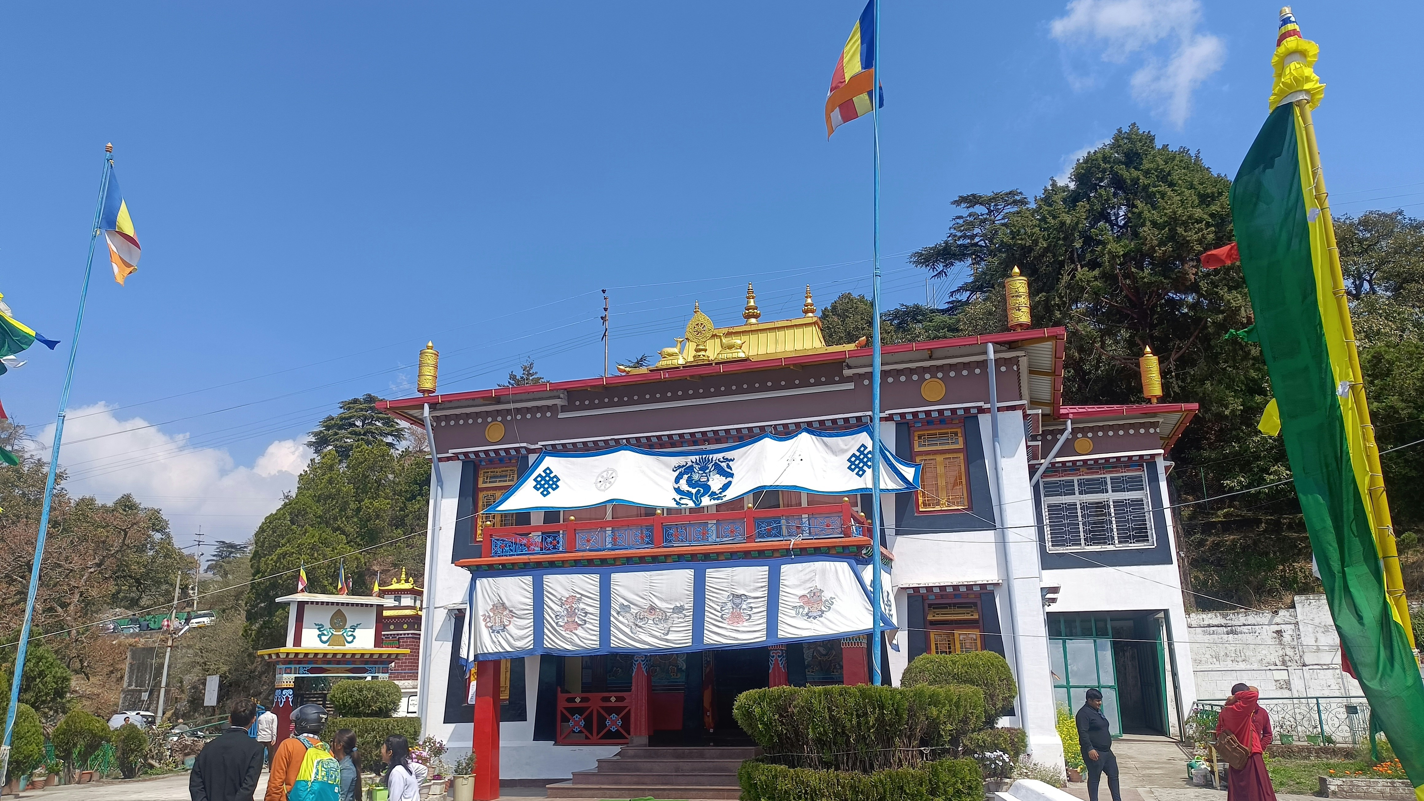 Colorful flags adorn a traditional temple under a clear blue sky.
