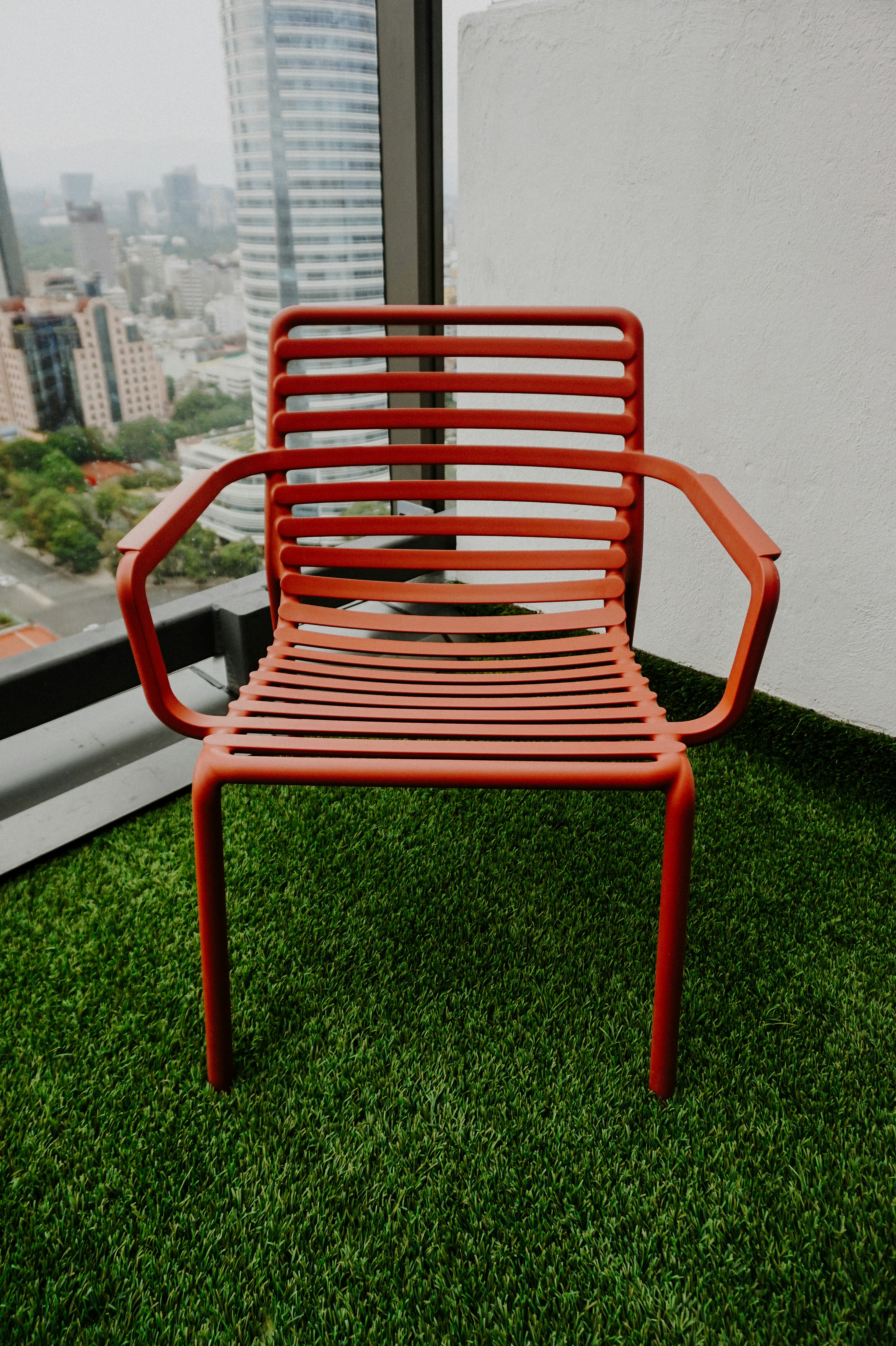 Crimson Slatted Chair Framing a Rooftop City Vista