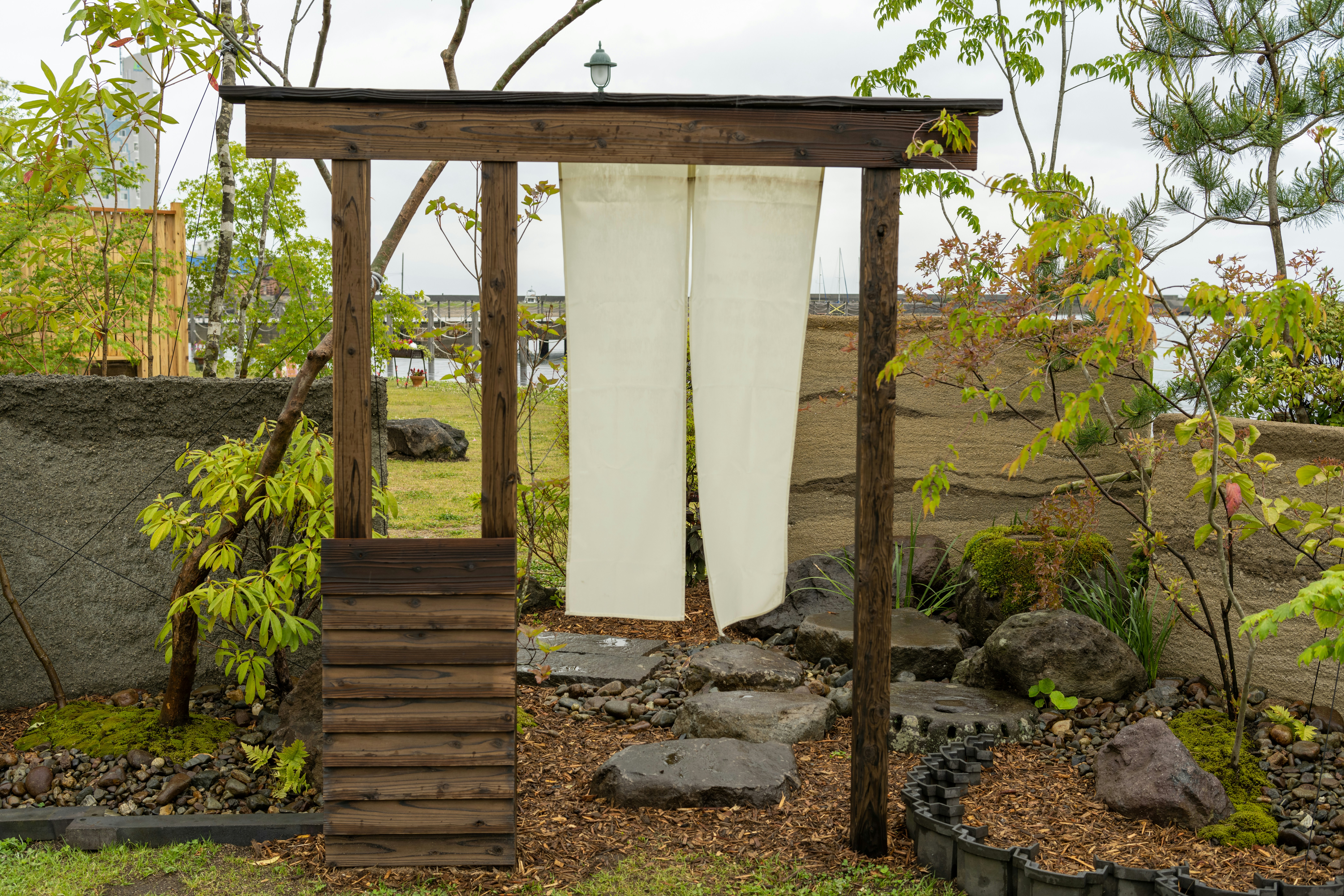 White Draped Portal Framed by Timber in a Tranquil Garden