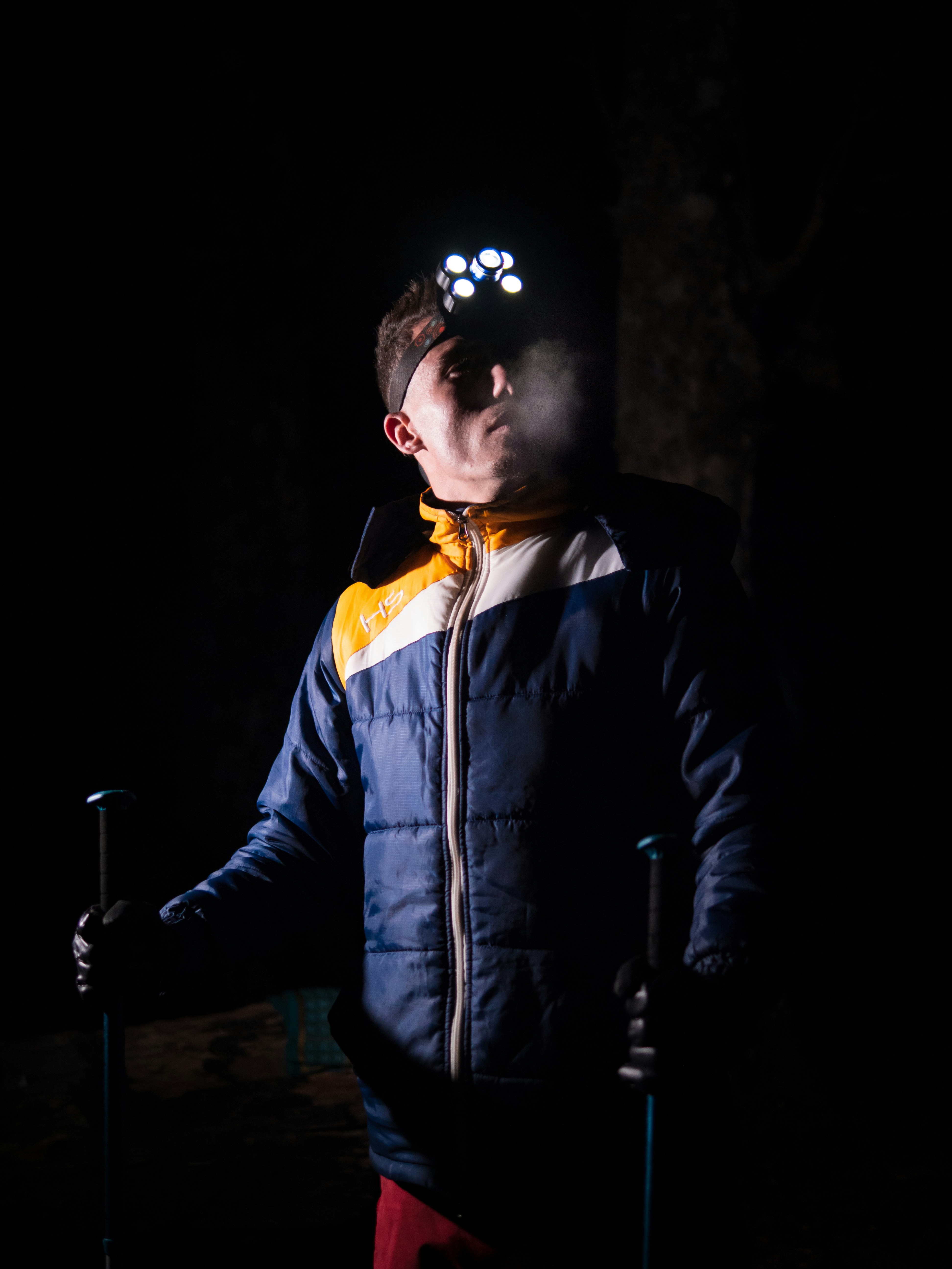 Night-hiking silhouette: headlamp halo and breath in the dark