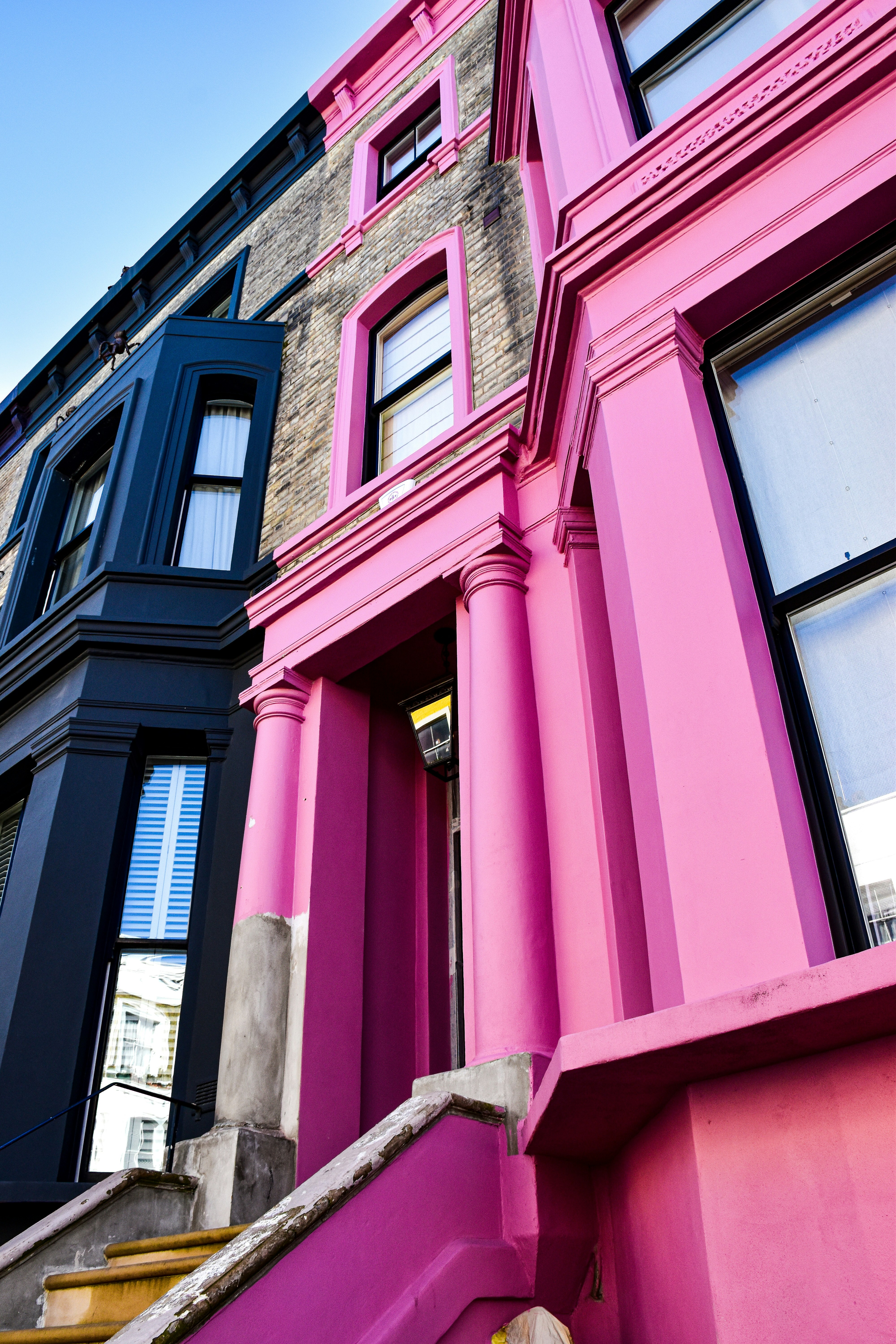 Foto Un edificio rosa con ventanas azules y una boca de incendios amarilla – Imagen Londres ...