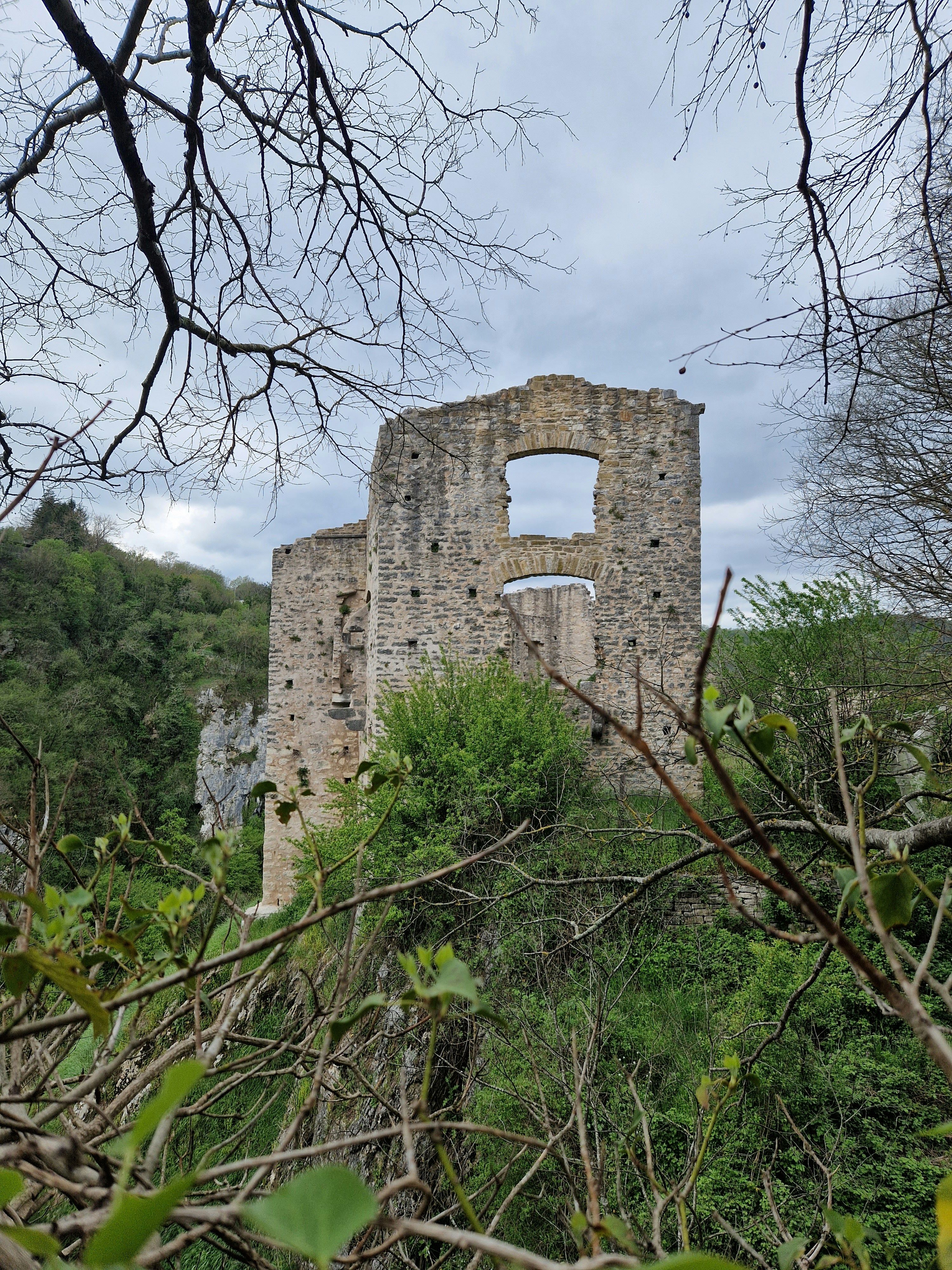 Stonewatch Arising Through Spring Foliage Beneath a Cloudy Sky