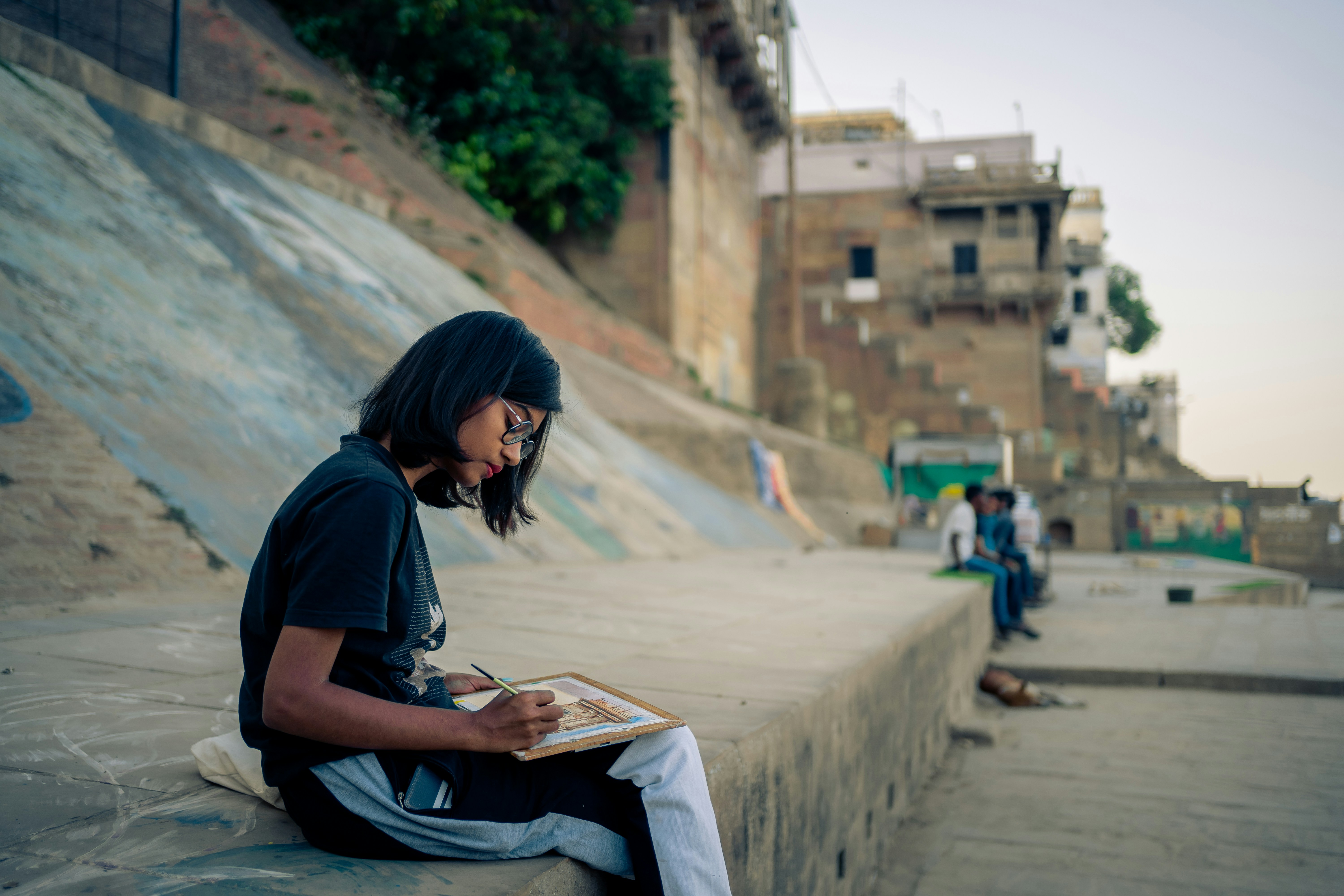 A woman sitting on a ledge reading a book photo – Free Woman Image on ...