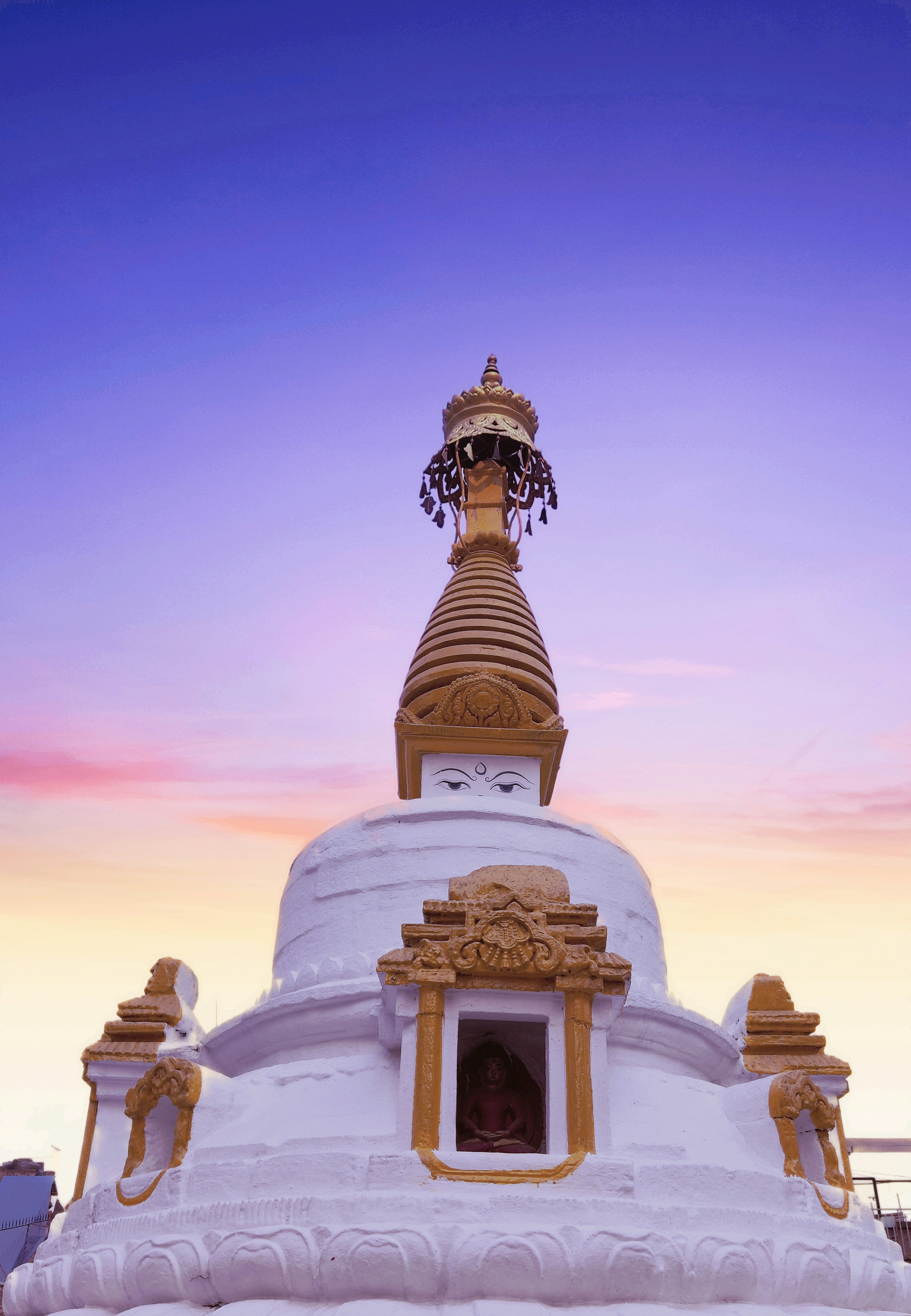 A majestic stupa adorned with intricate golden details, set against a vibrant twilight sky. The peaceful structure invites contemplation.