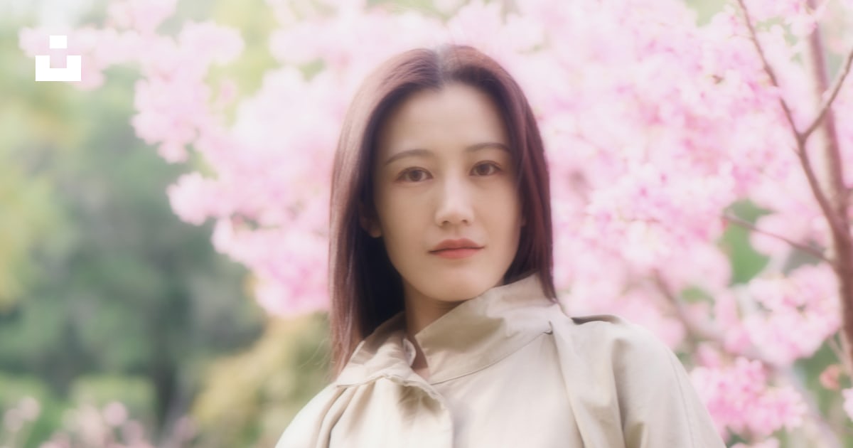 Una Mujer Parada Frente A Un árbol Con Flores Rosadas Foto Imagen De