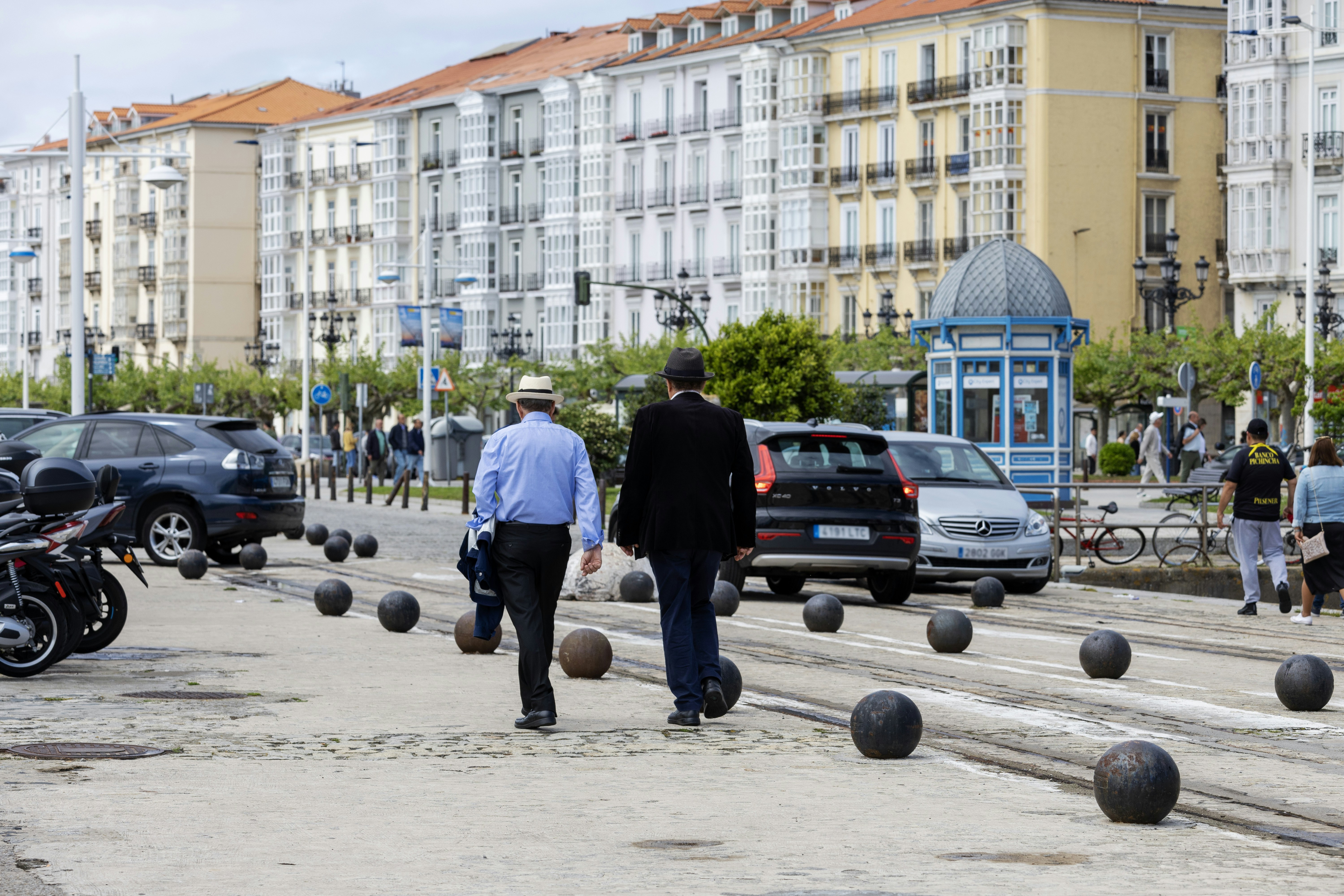 A couple of men walking down a street next to parked cars photo – Free ...