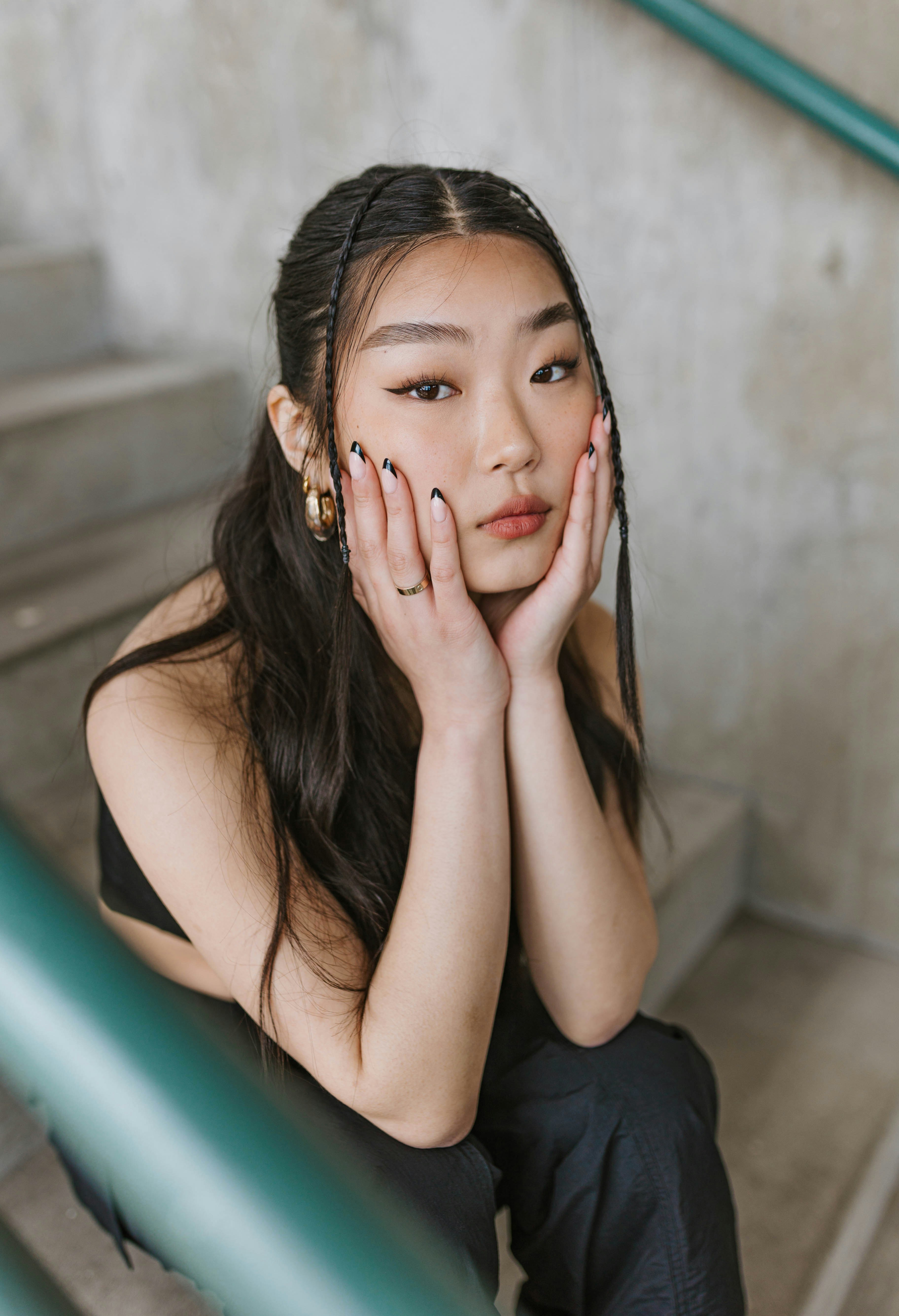 A woman sitting on a set of stairs with her hands on her face photo ...