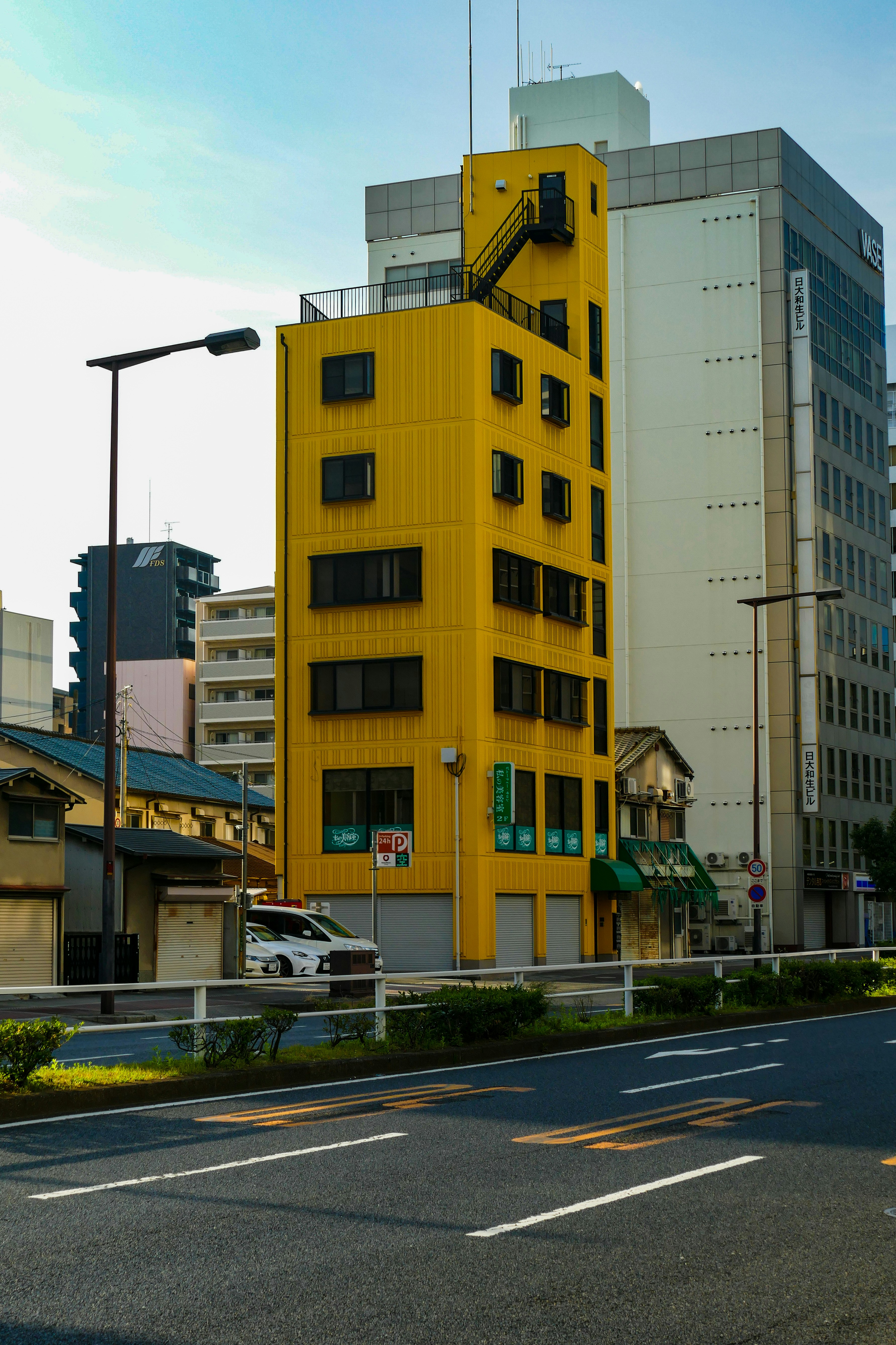 A tall yellow building sitting on the side of a road photo – Free Osaka ...