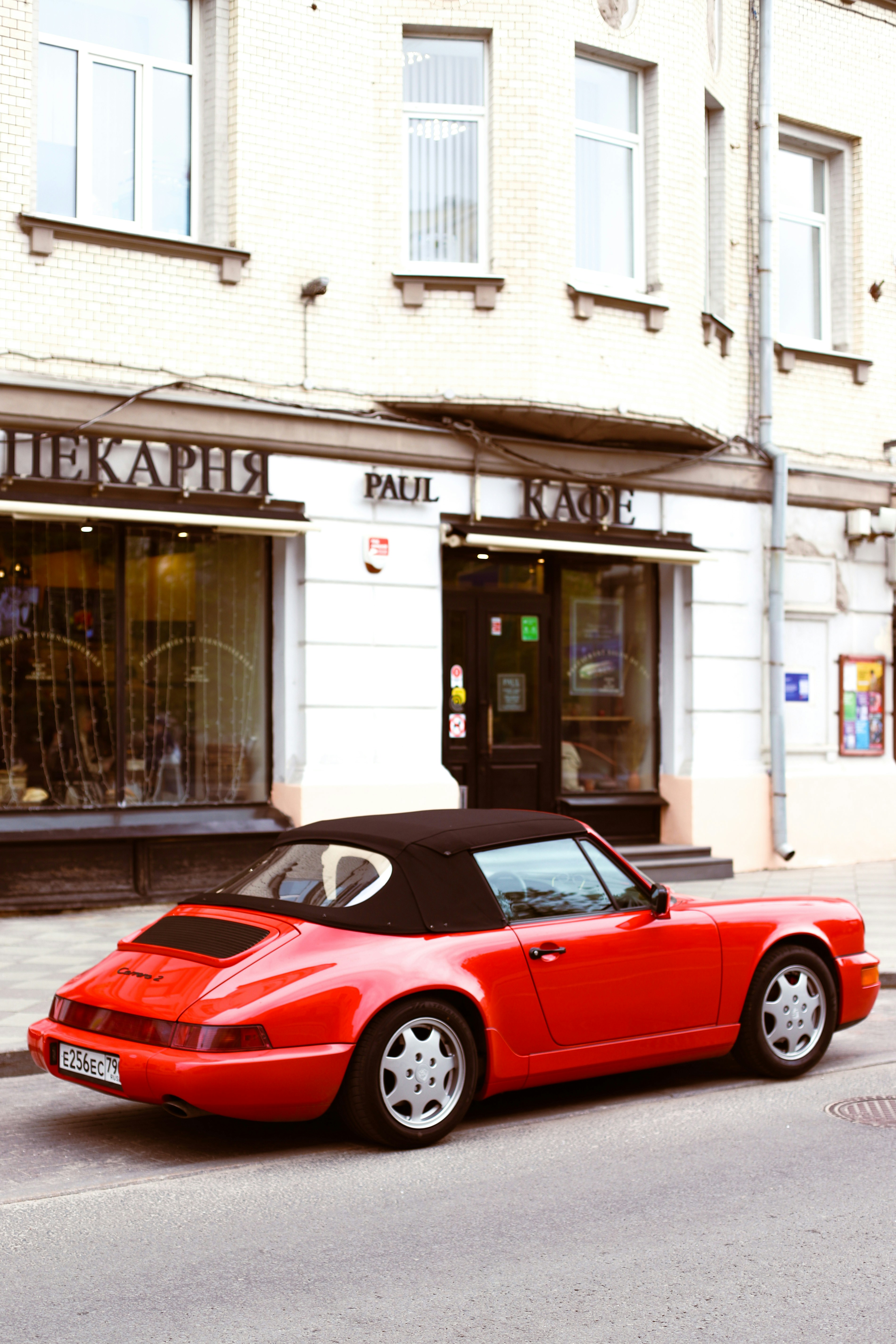 Crimson Cabriolet at a cafe-lined city curb