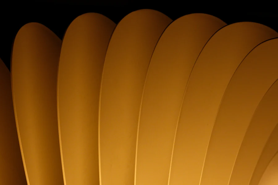 Layered golden curved forms arc across a dark background, creating a soft abstract pattern. The composition is warm and minimalist with smooth gradients and shadowed edges.