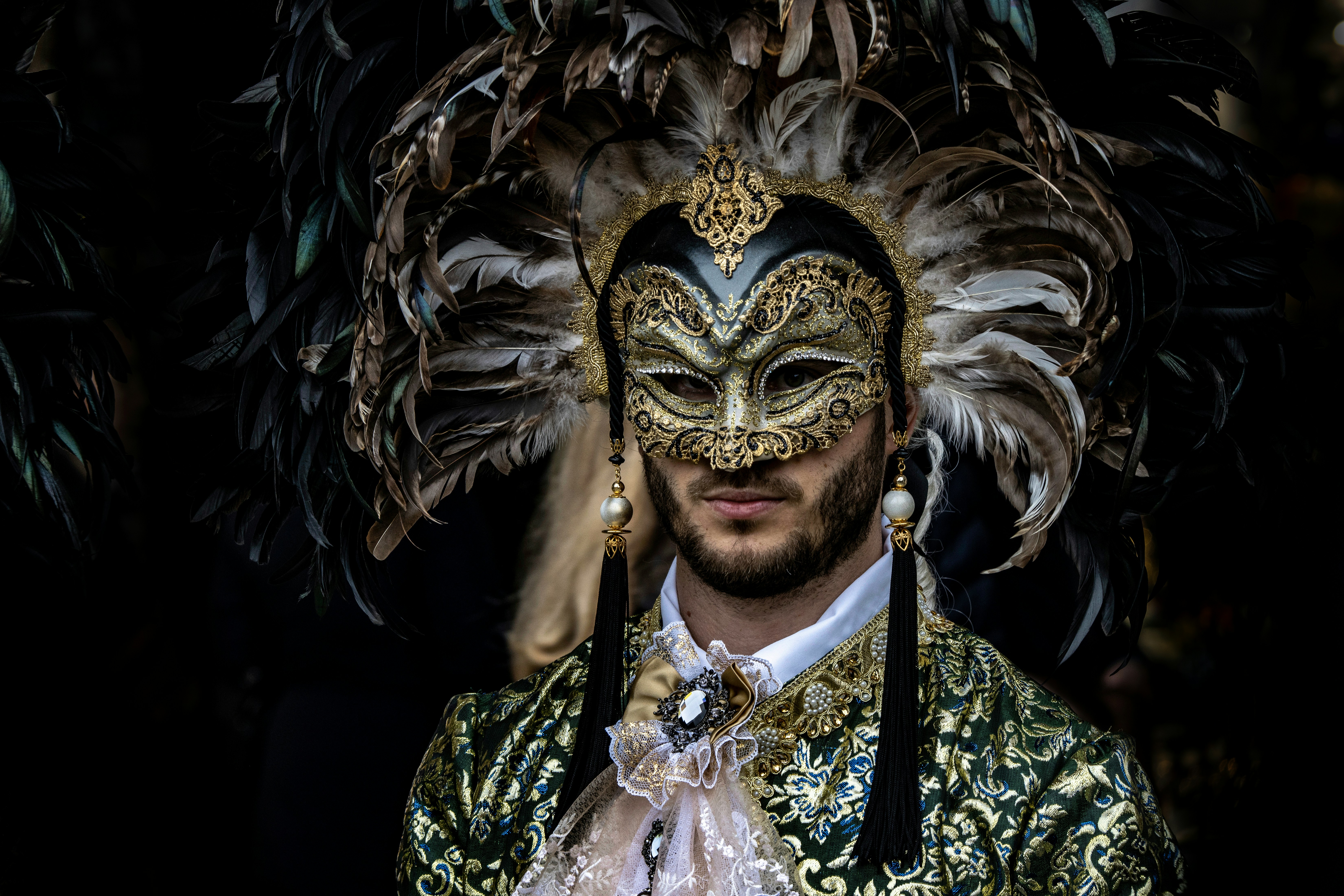 A man wearing a mask with feathers on his head photo – Free Man Image ...