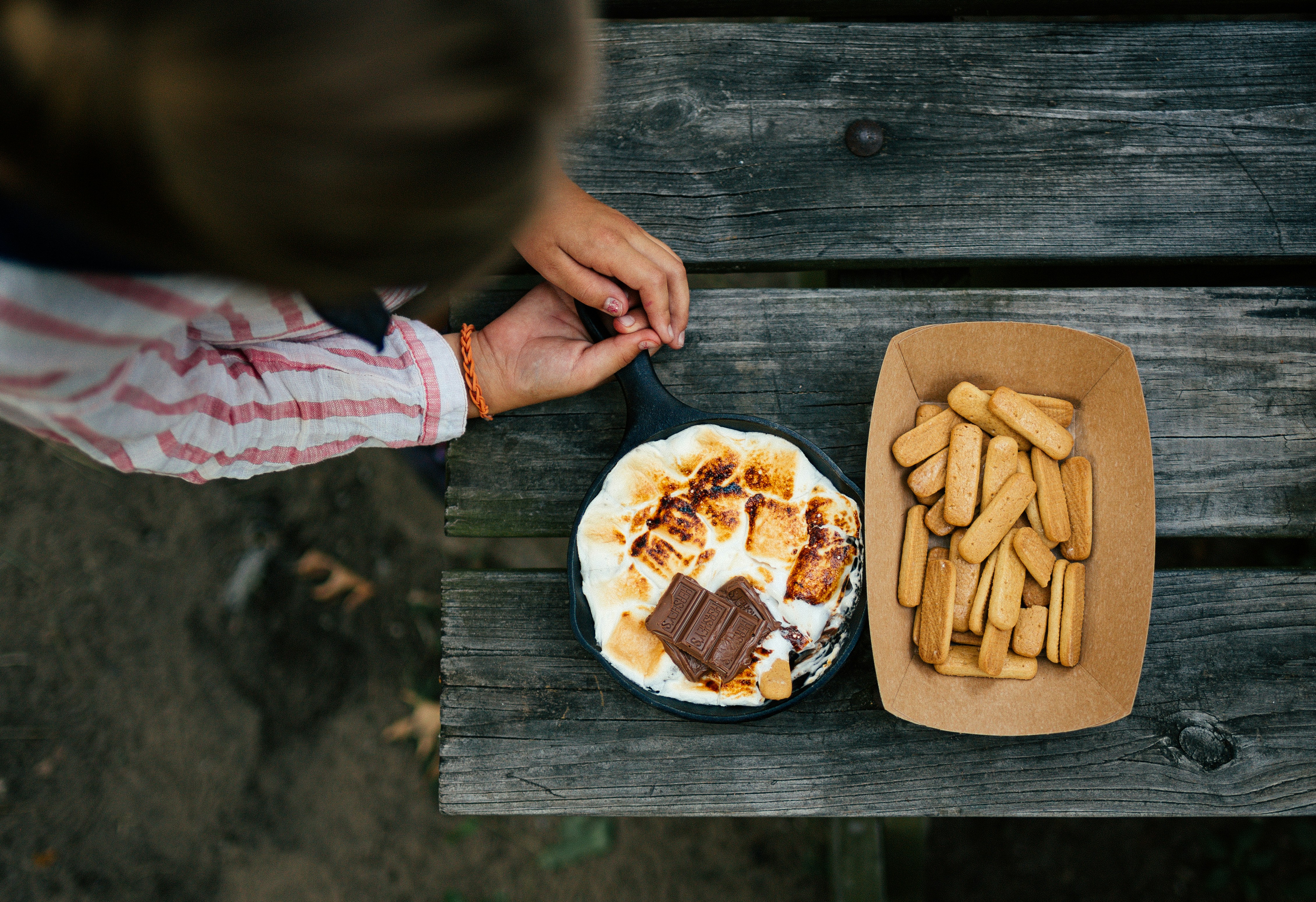 Overhead View: Toasted Marshmallows and Chocolate on a Weathered Picnic Board