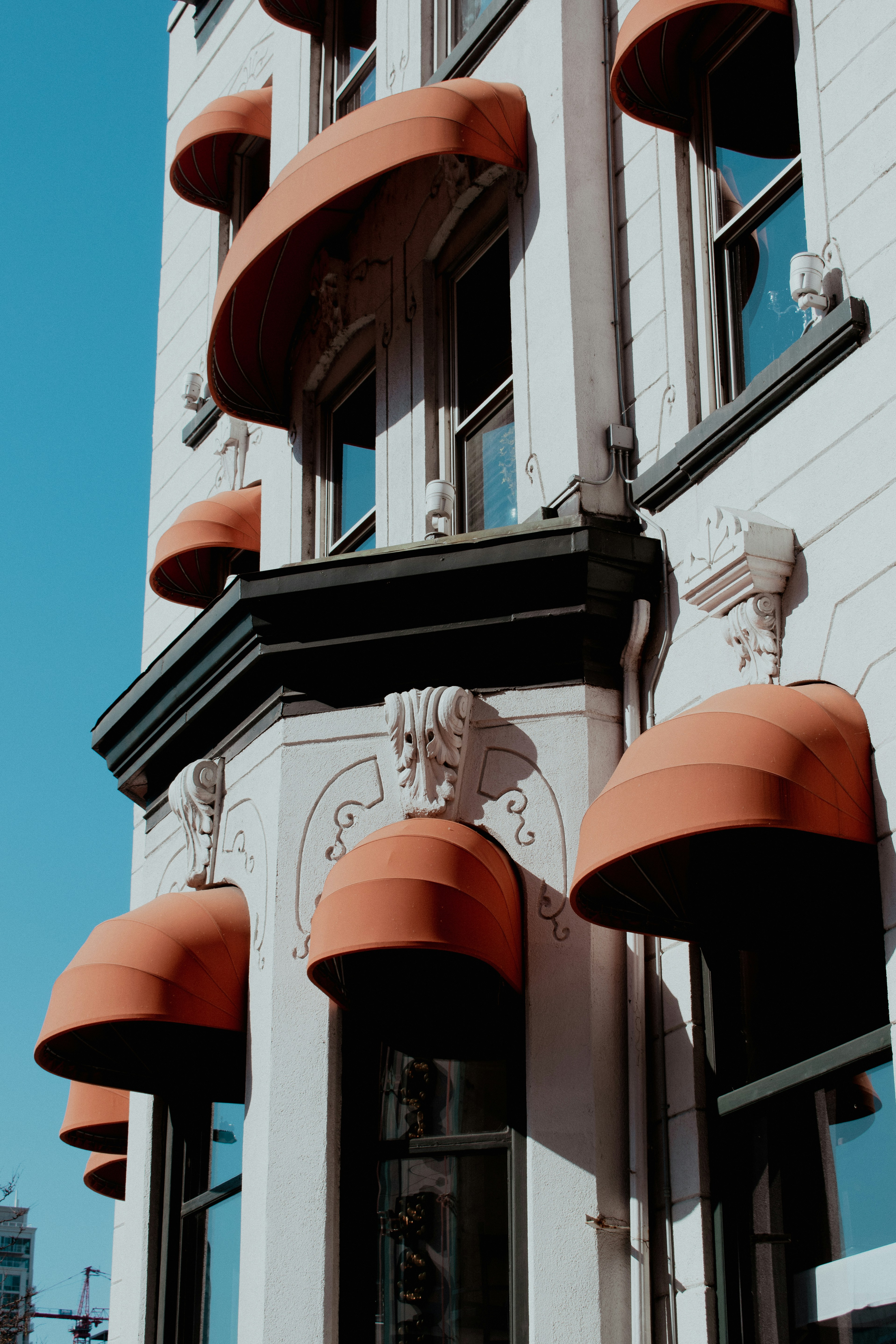 Historic building facade featuring ornate details and vibrant orange awnings against a clear blue sky.