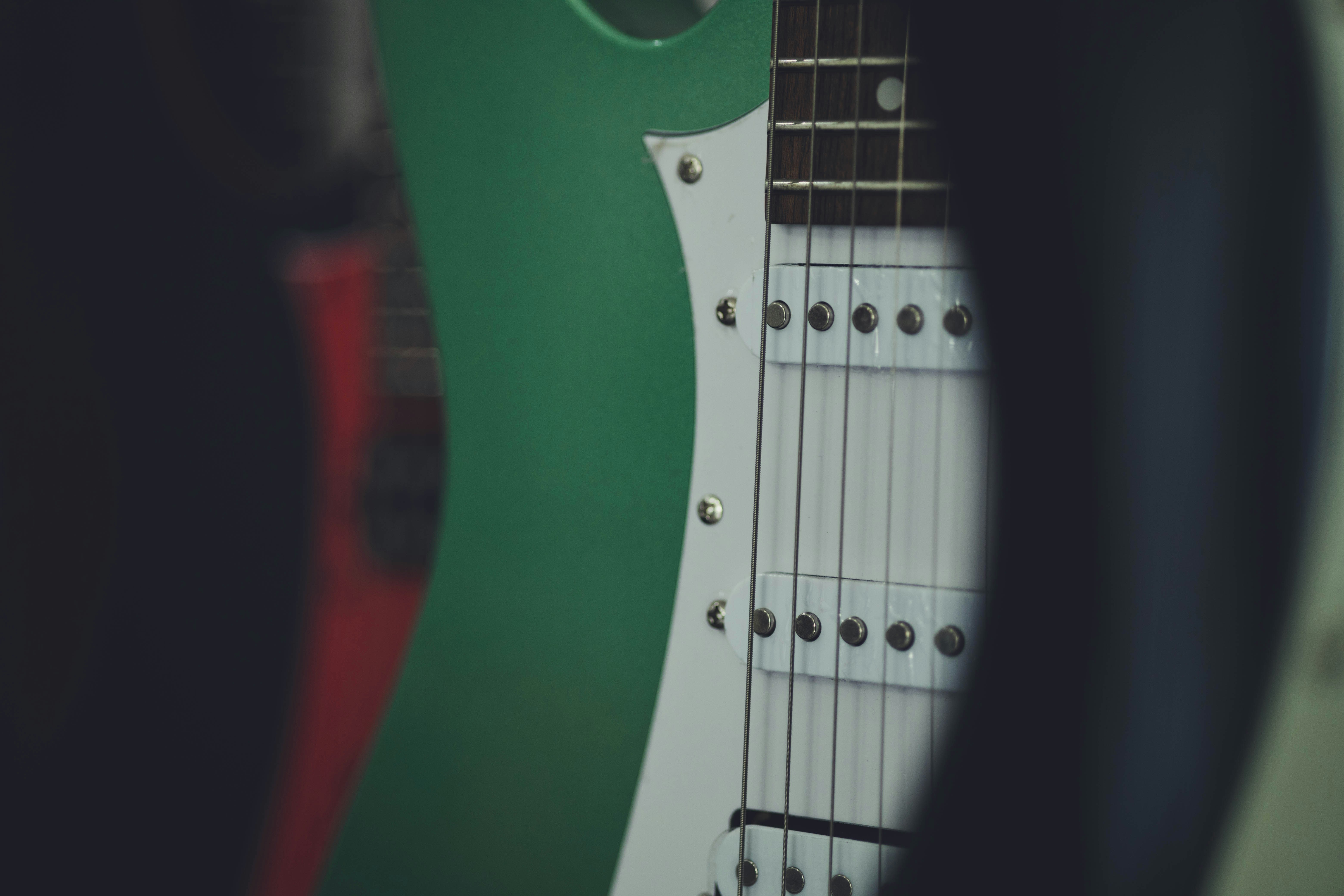 Mint-Green Electric Guitar Close-Up: Strings, Pickguard, and Shadowed Frame