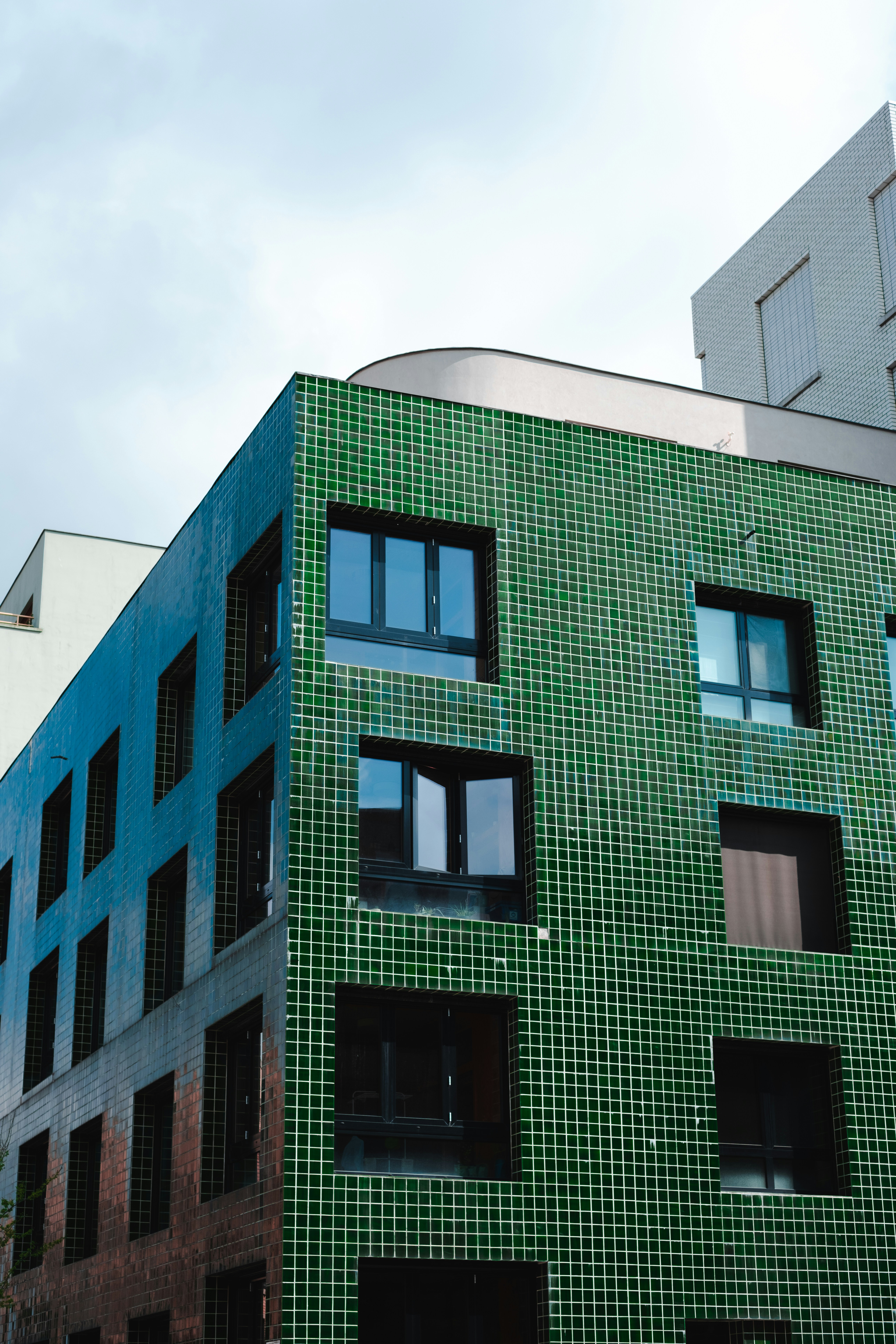 Emerald Mosaic: The Corner of a Green-Tiled Modern Building
