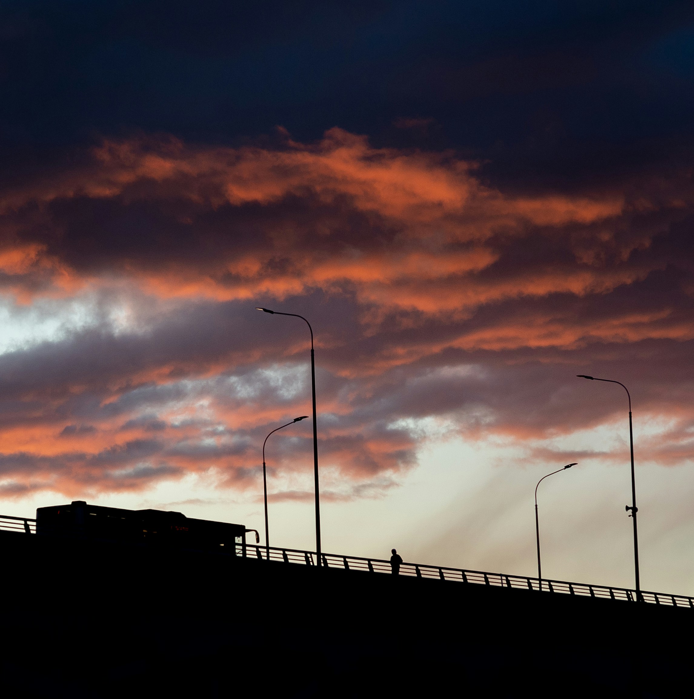 Lone Silhouette on a Bridge Under a Molten Sunset