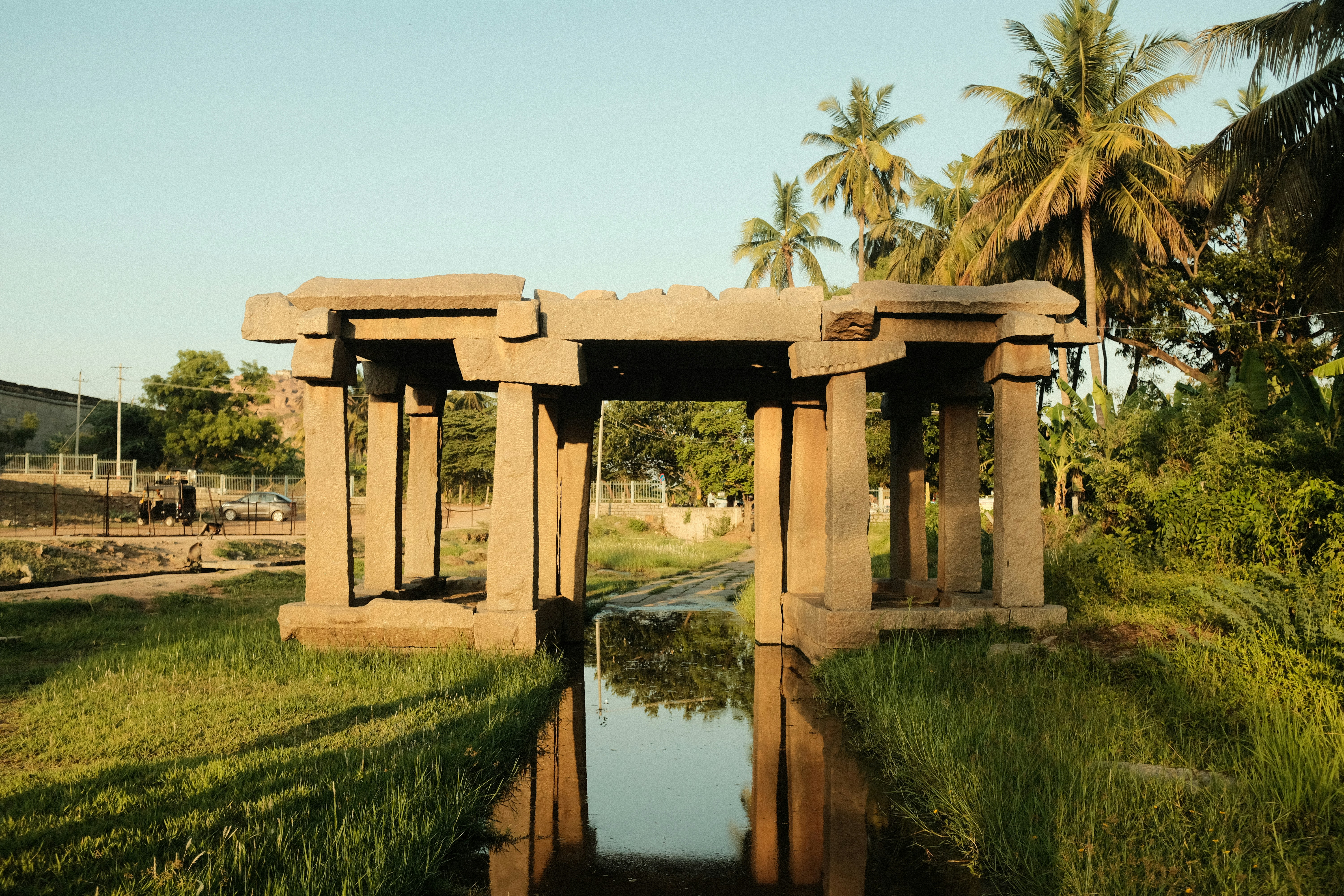 Stone Gate Over Water: A Quiet Temple-like Structure Framed by Palm Trees