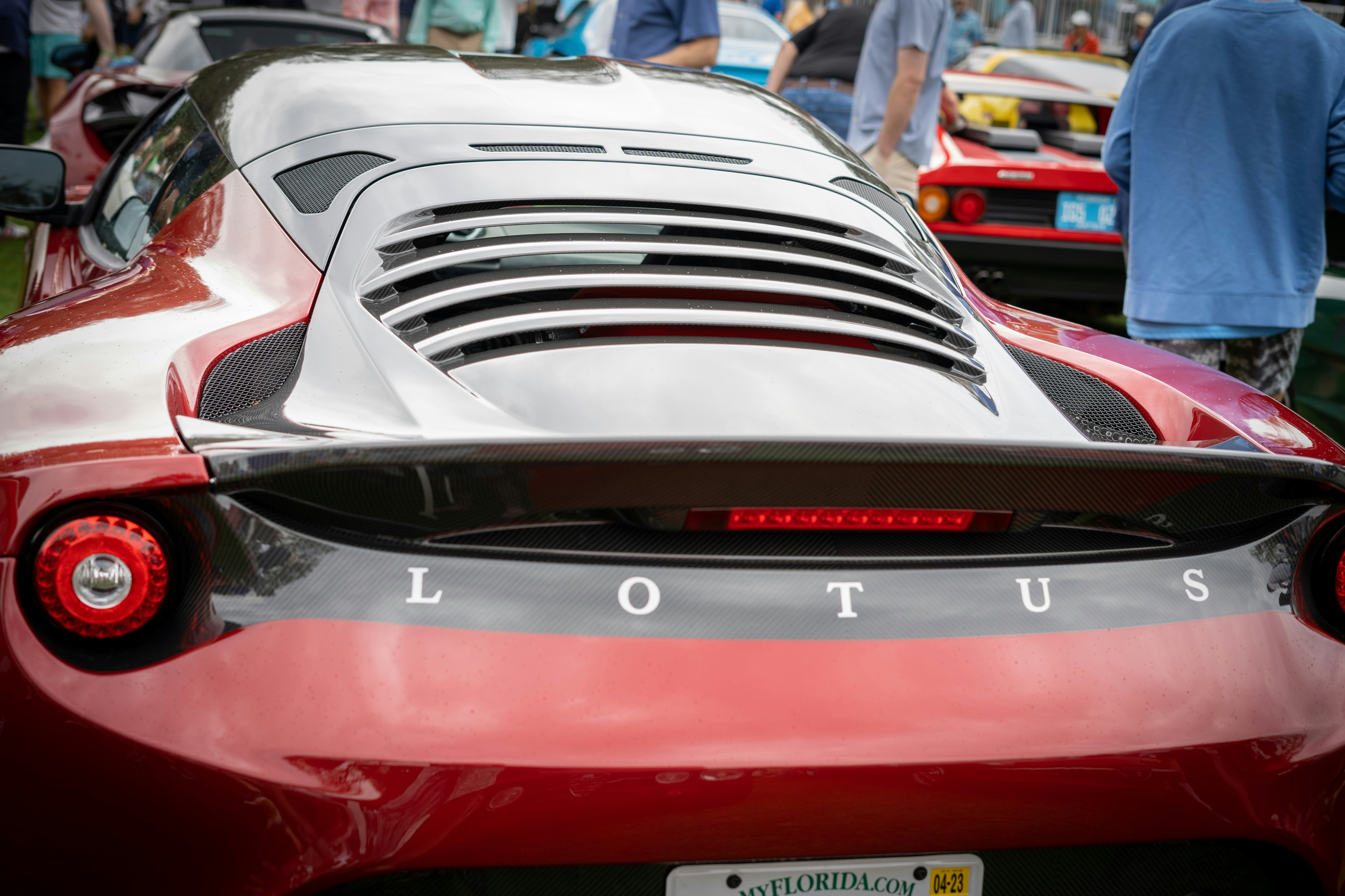 Rear view of a red Lotus sports car with distinct vented engine cover and sleek design.
