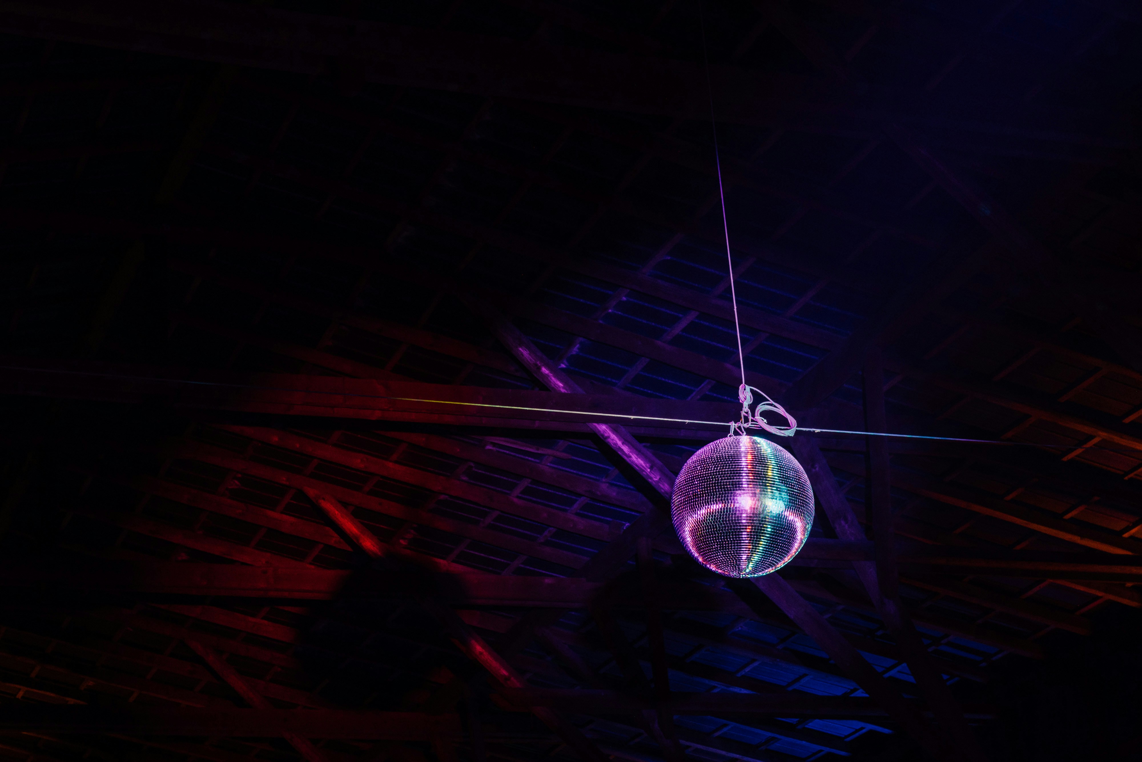 Neon Prism in the Dark: A Suspended Disco Ball Under Colored Rafters
